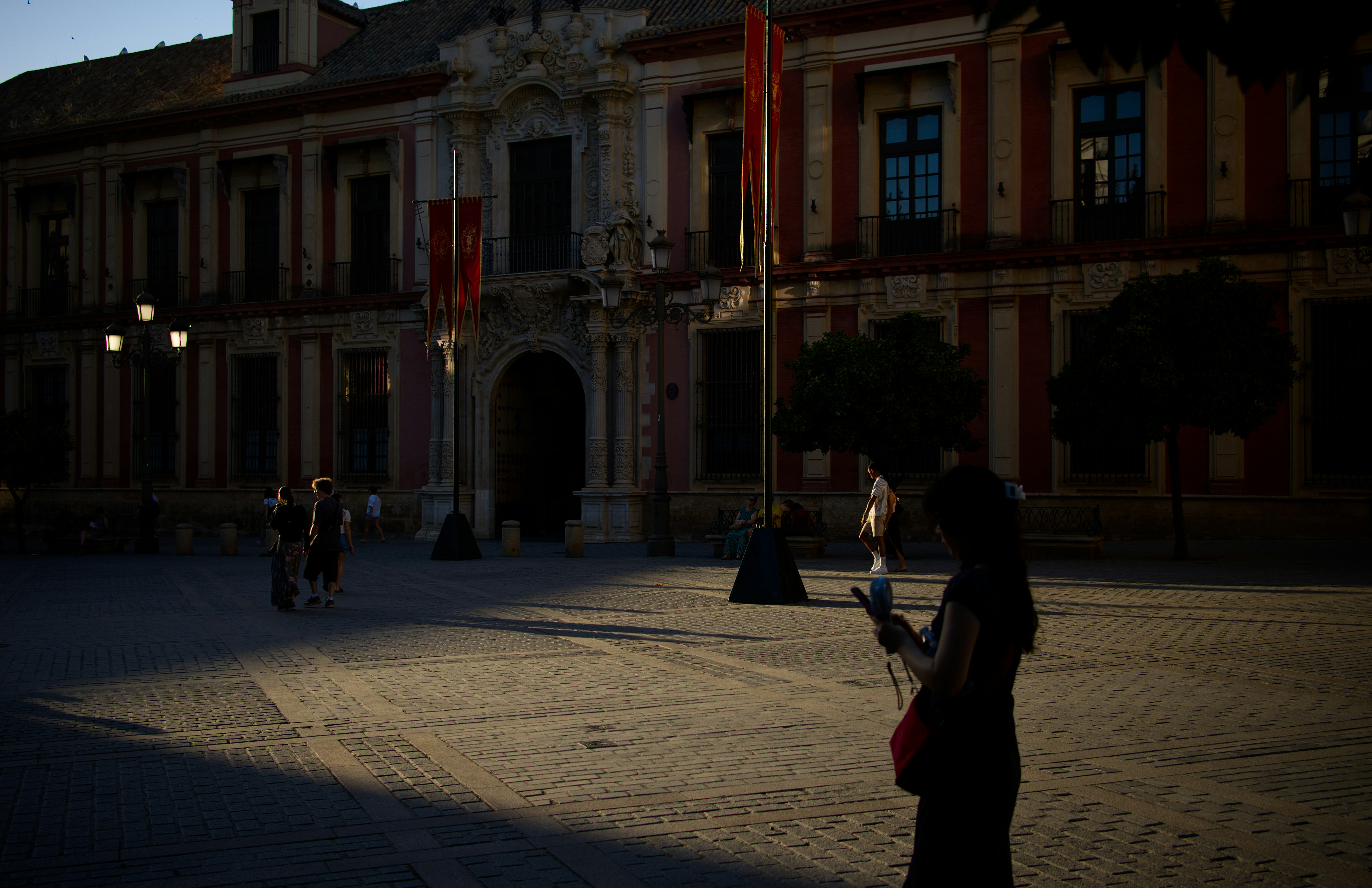 Quiet Street at Dusk: A Woman with a Phone Steps into Shadowed Light
