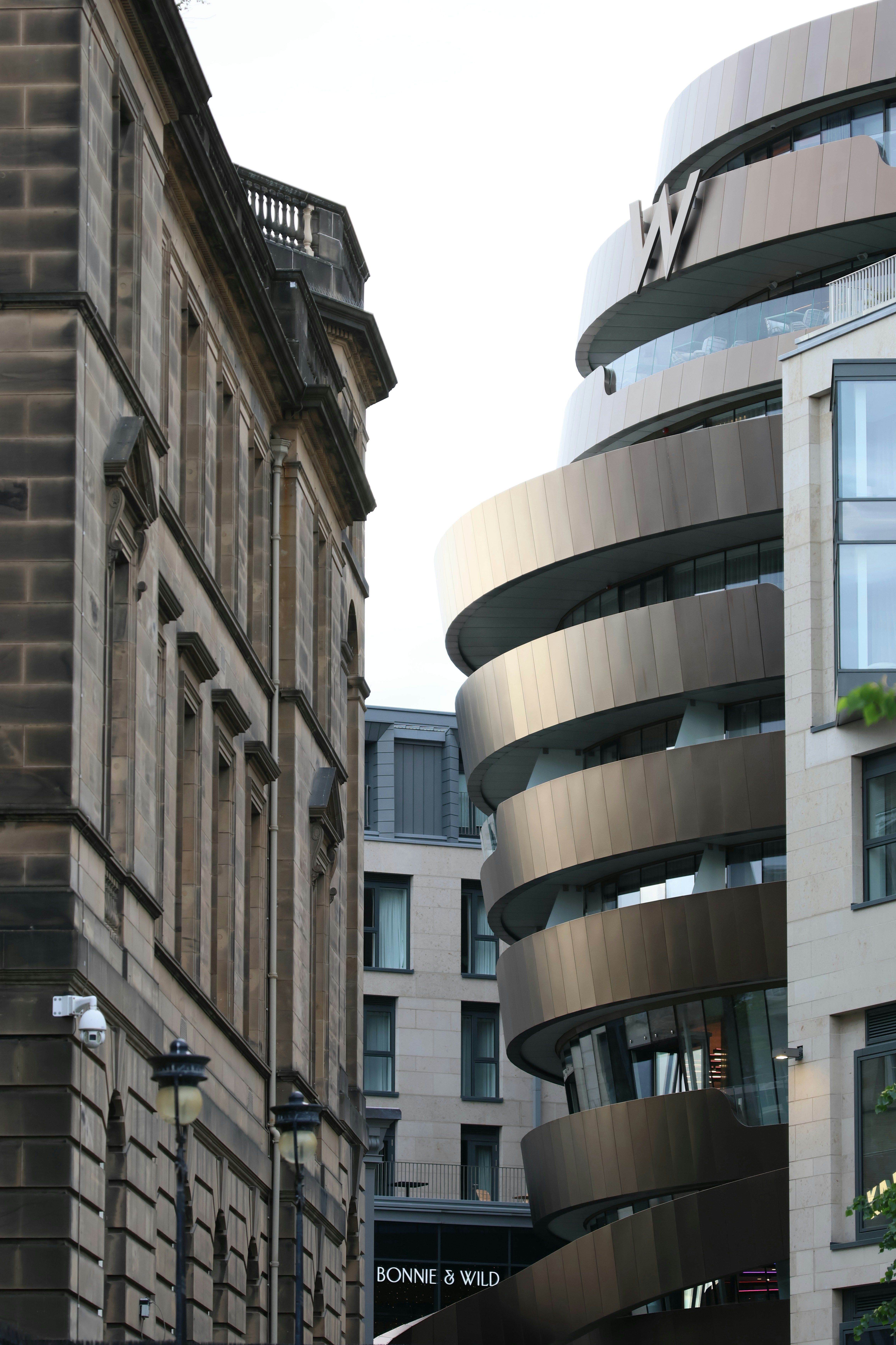 Curved Facades in Contrast: Timeworn Stone Meet Modern Bronze