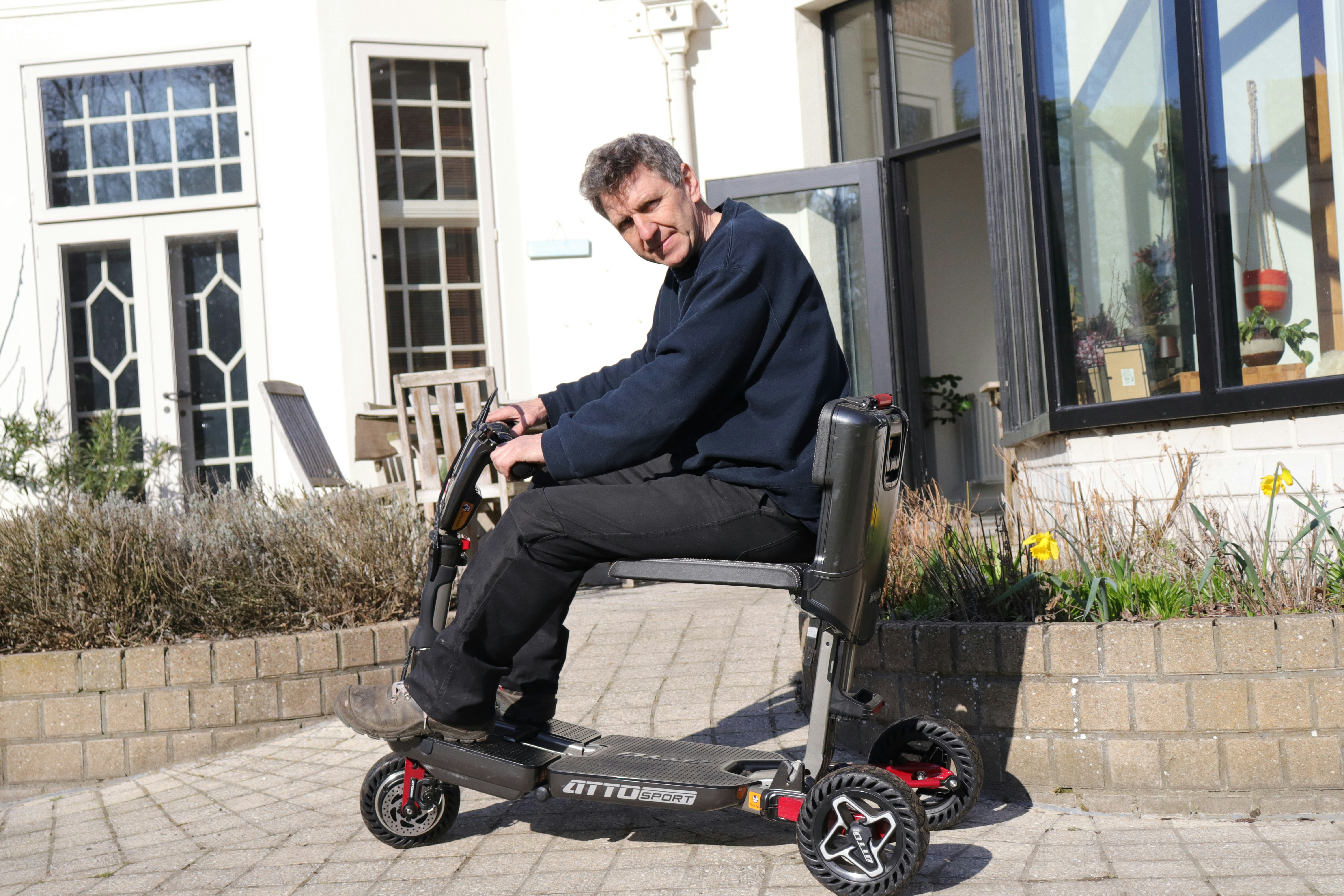 Man on a compact mobility scooter parks beside a modern storefront