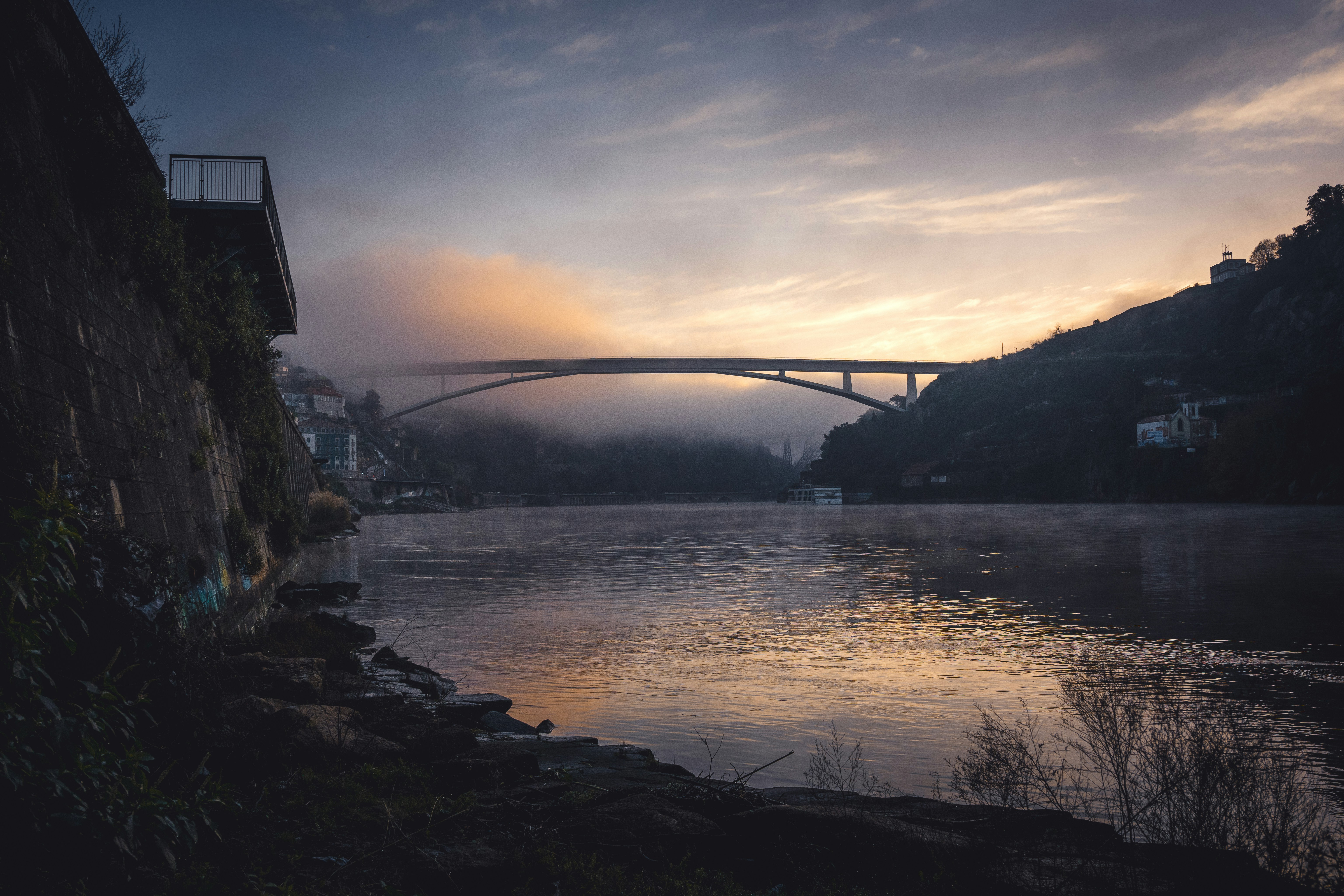 Misty sunrise over a river with a bridge.