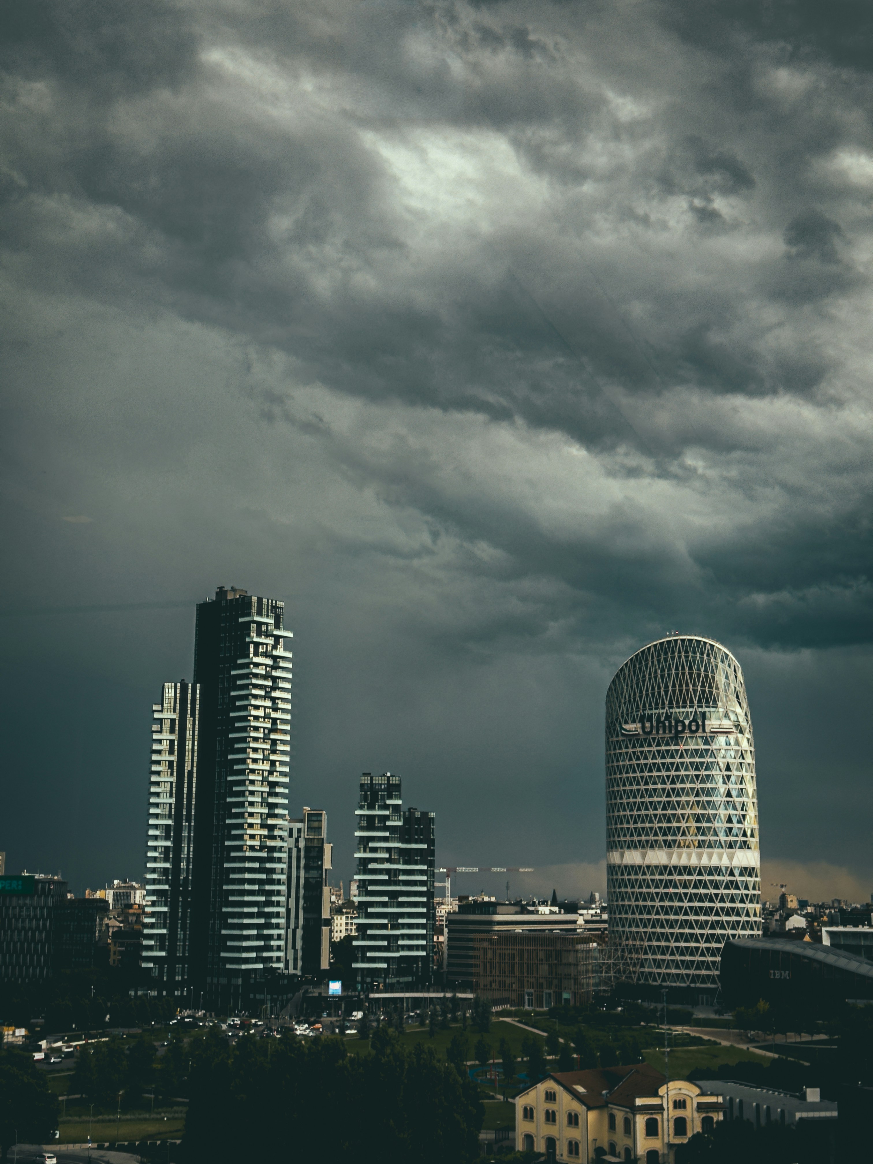 Dark cityscape with modern skyscrapers under a dramatic cloudy sky.