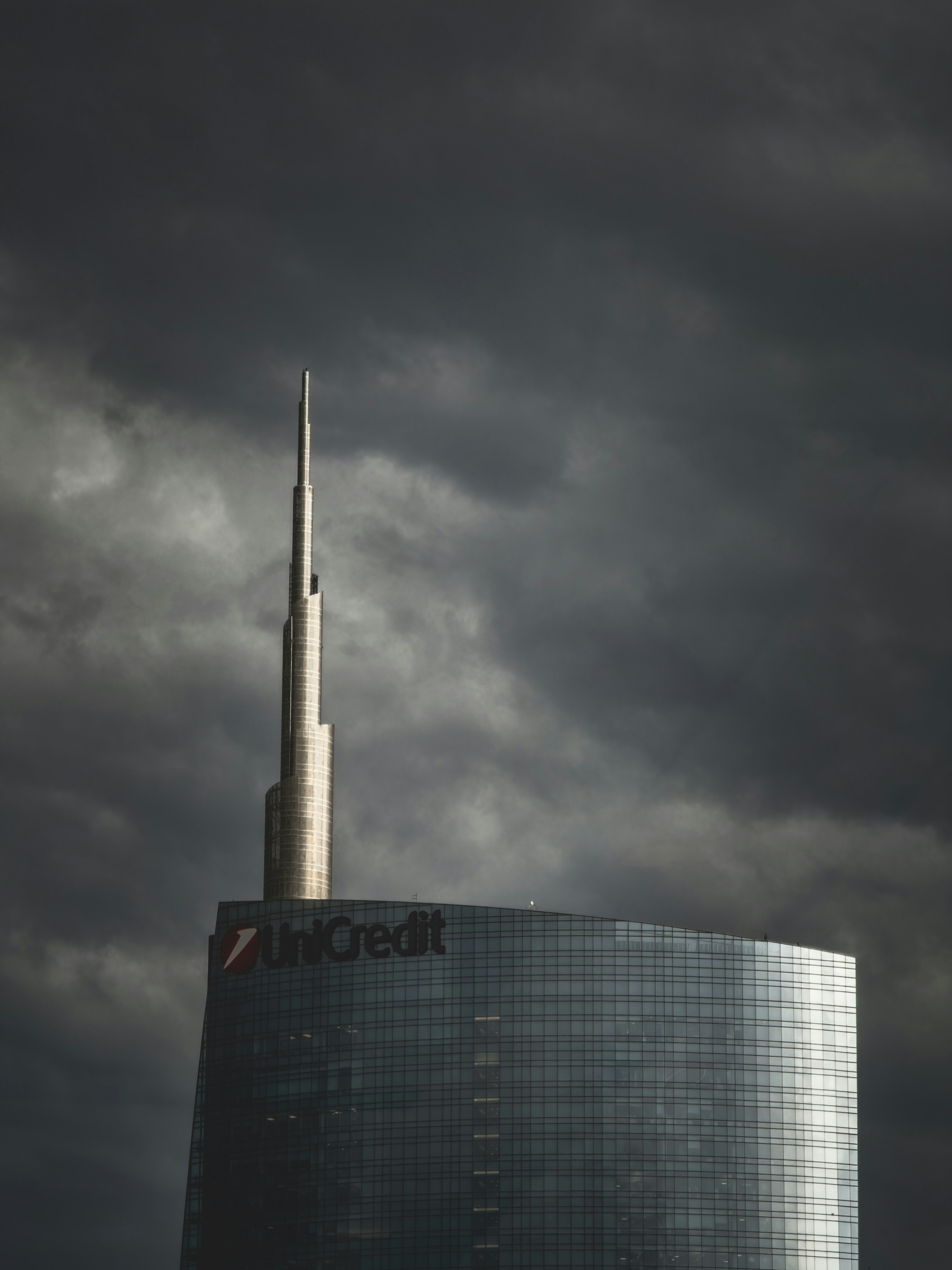 Unicredit tower against a dramatic, dark, cloudy sky.