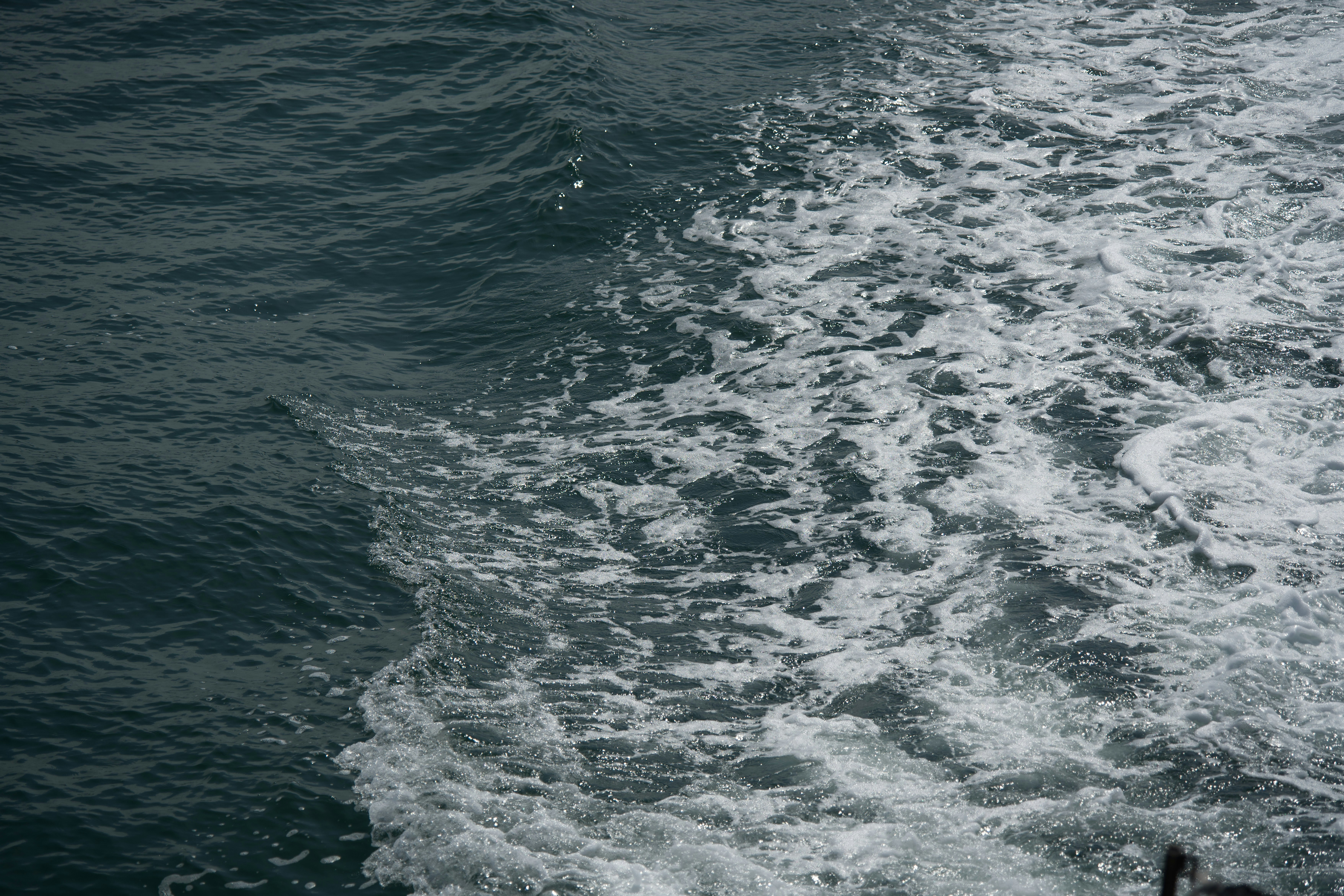 Churning Wake: Sunlit Sea Sweep in Midday Light