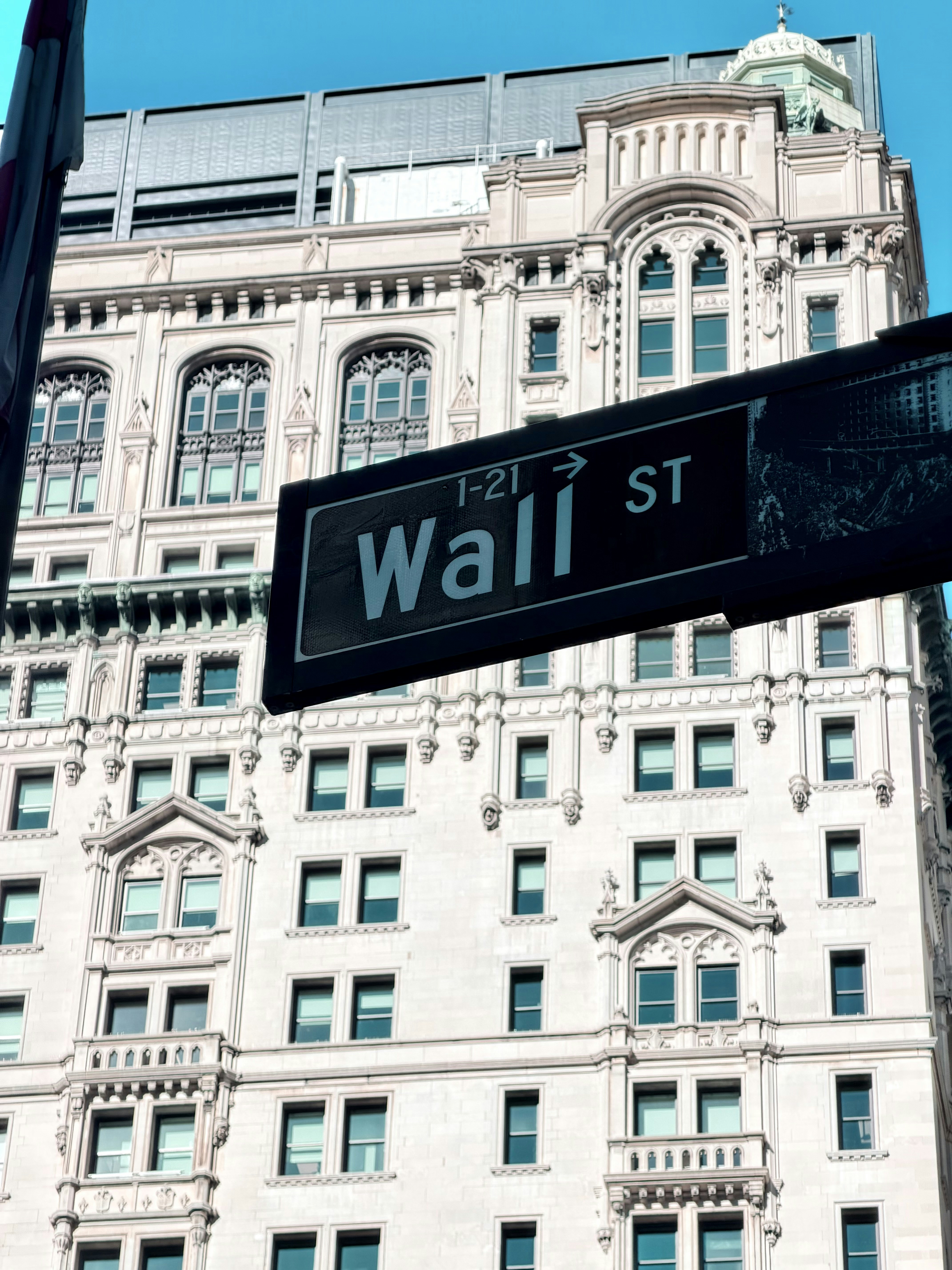 Wall street sign in front of a historic building.
