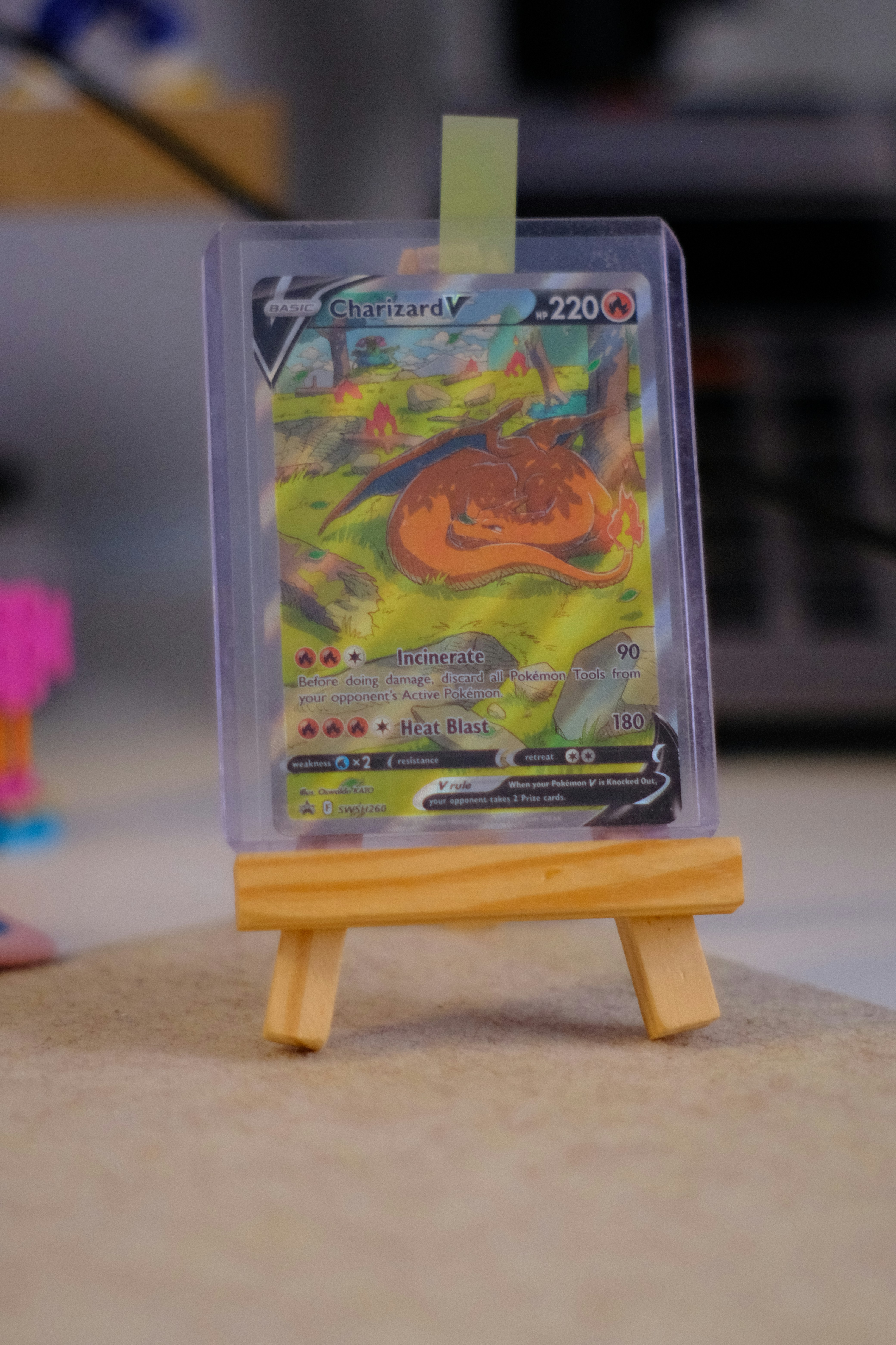 Pokémon charizard v card on a miniature wooden easel.