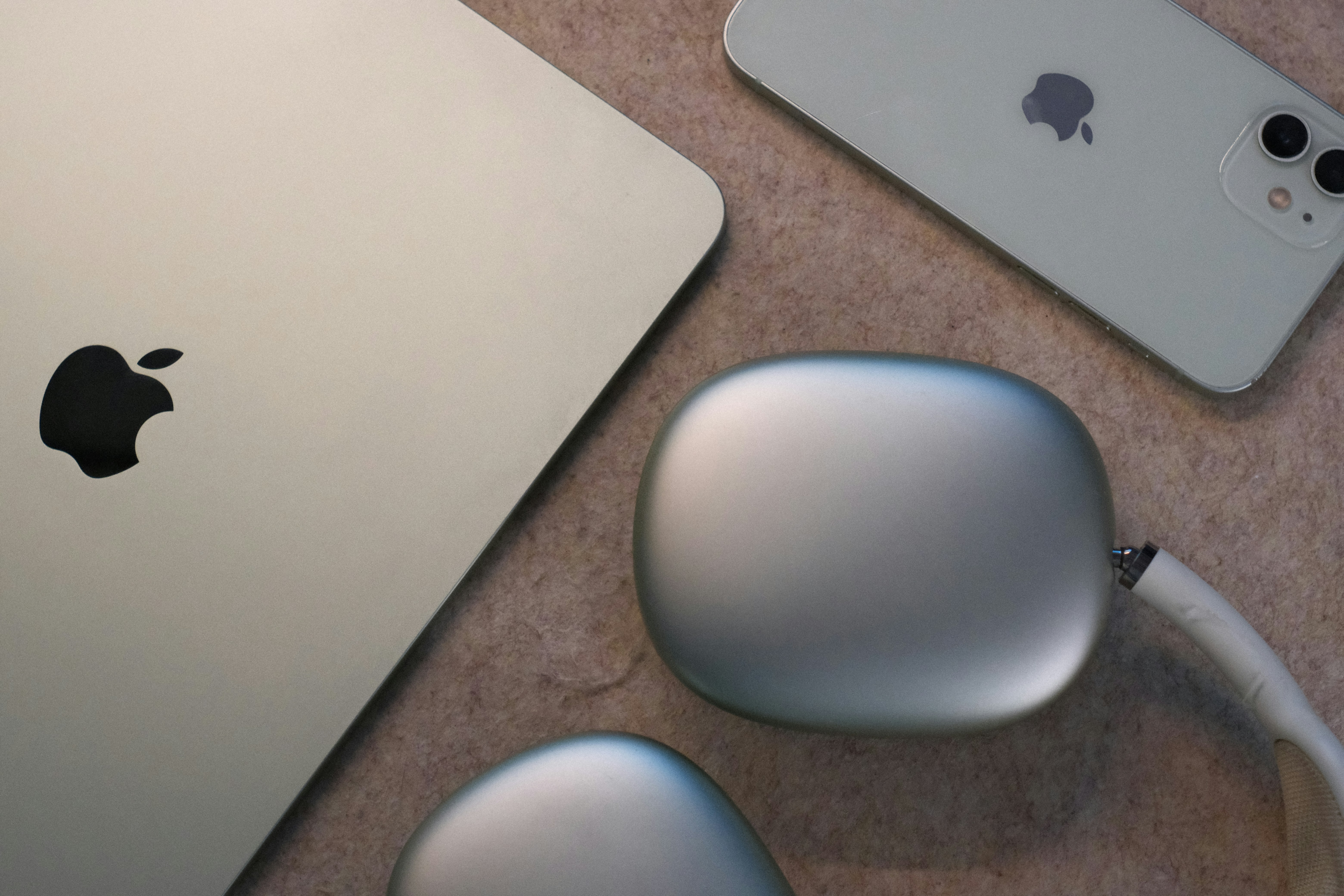 Silver apple macbook, iphone, and airpods max headphones.