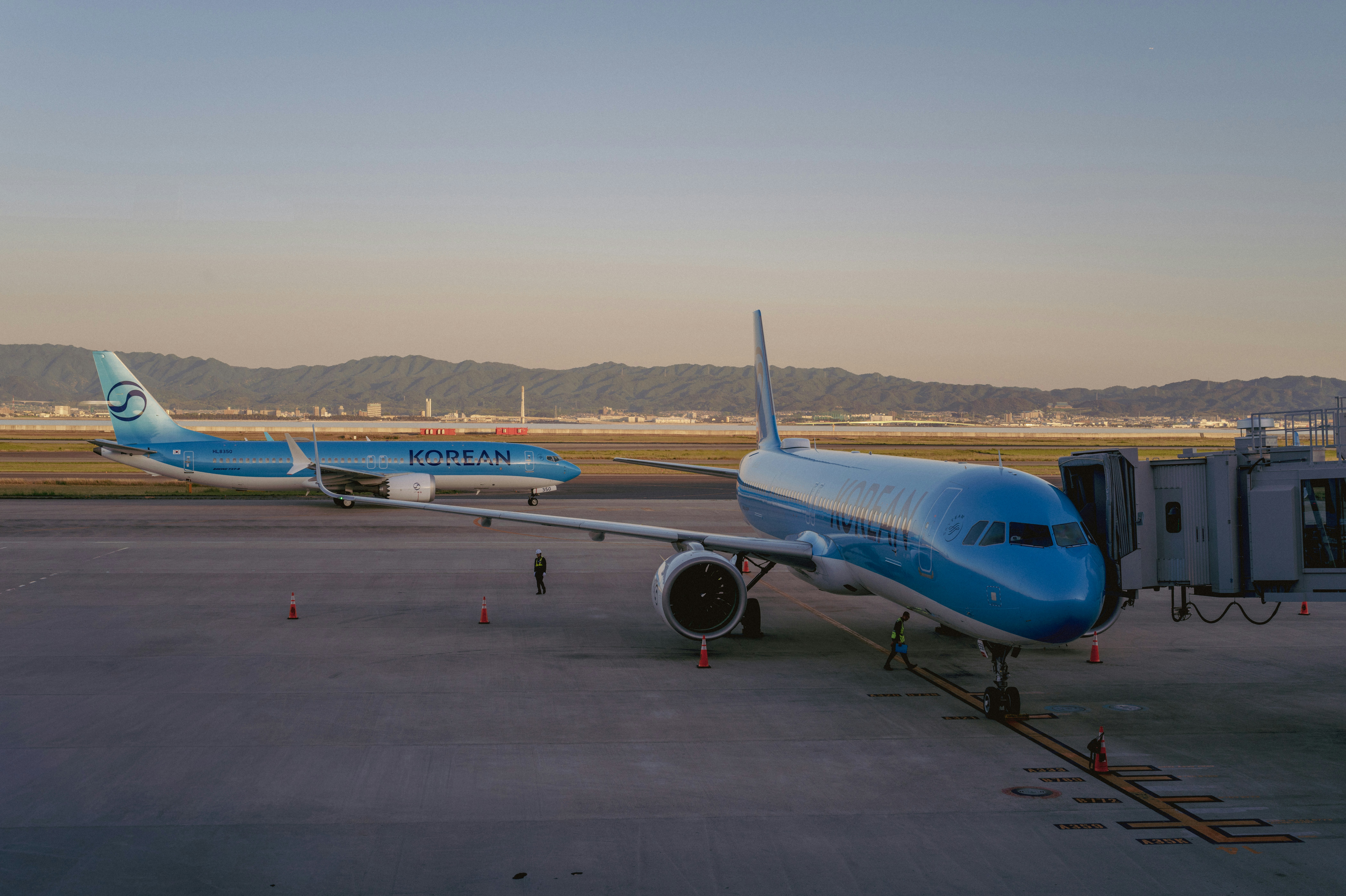 Two blue airplanes on an airport tarmac at sunset.