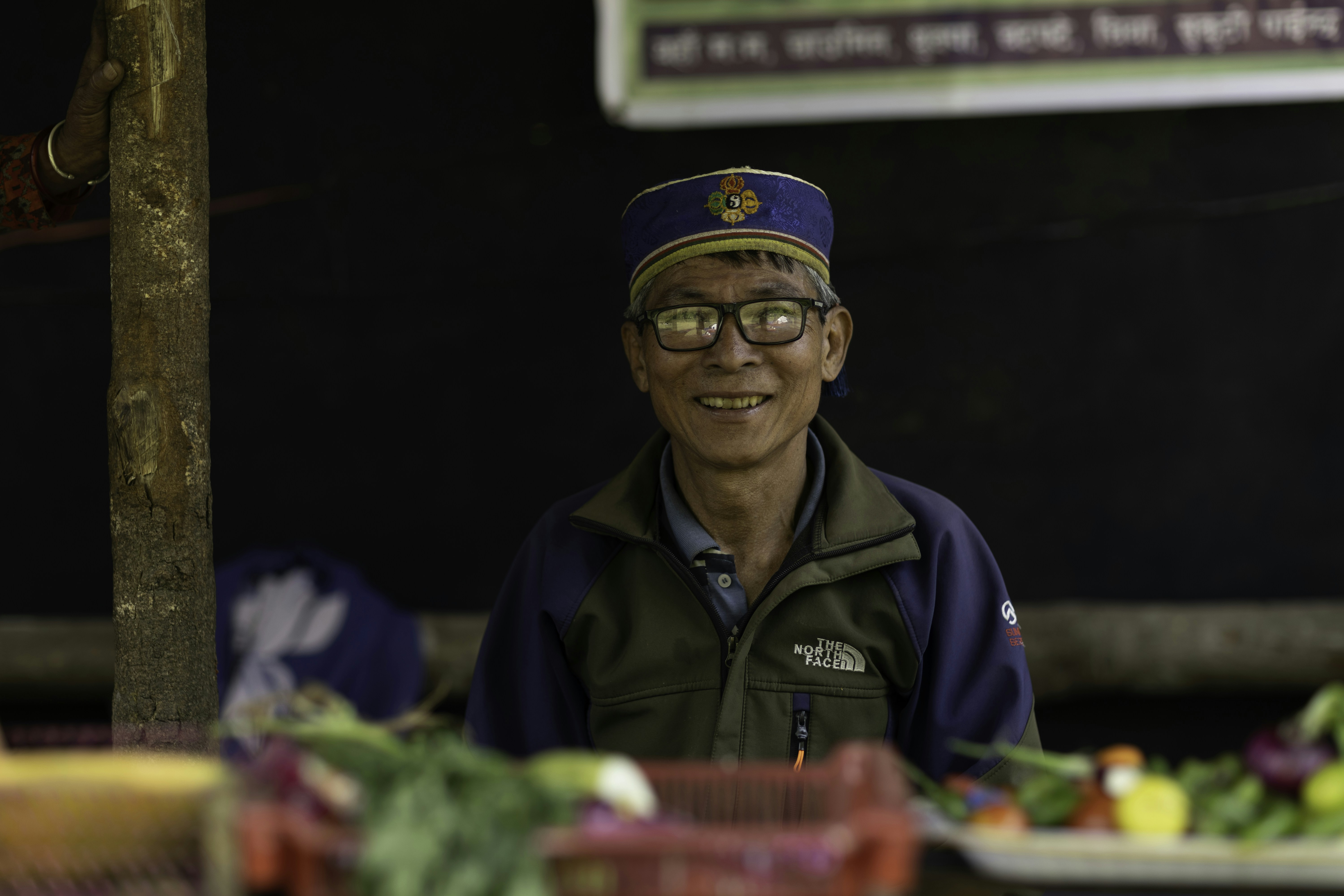 Smiling Vendor Under a Market Stall Umbrella