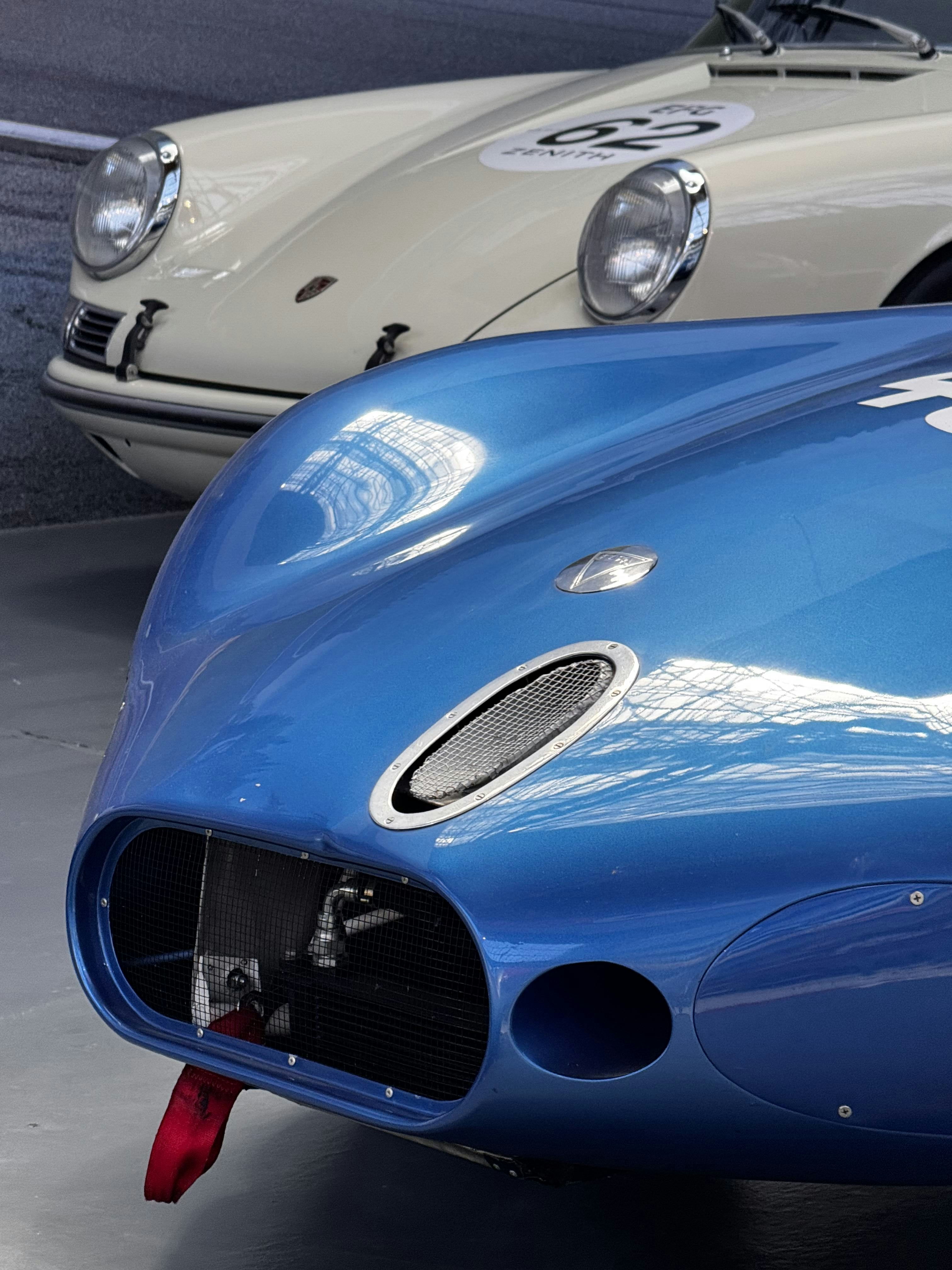 Curves in Focus: A Blue Jaguar and Cream Porsche Stacked in a Classic Car Lineup