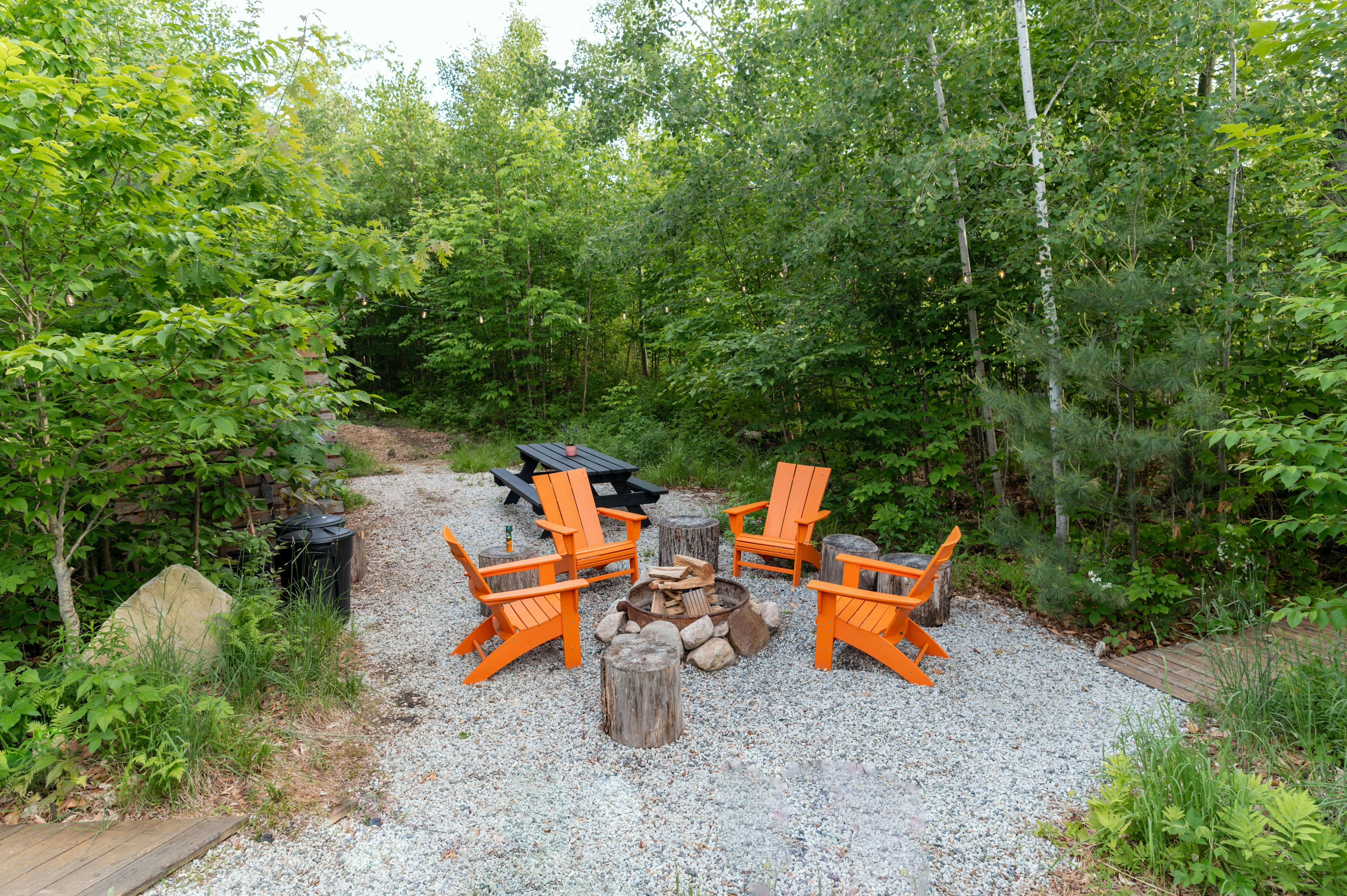 Outdoor fire pit with orange chairs and a picnic table.