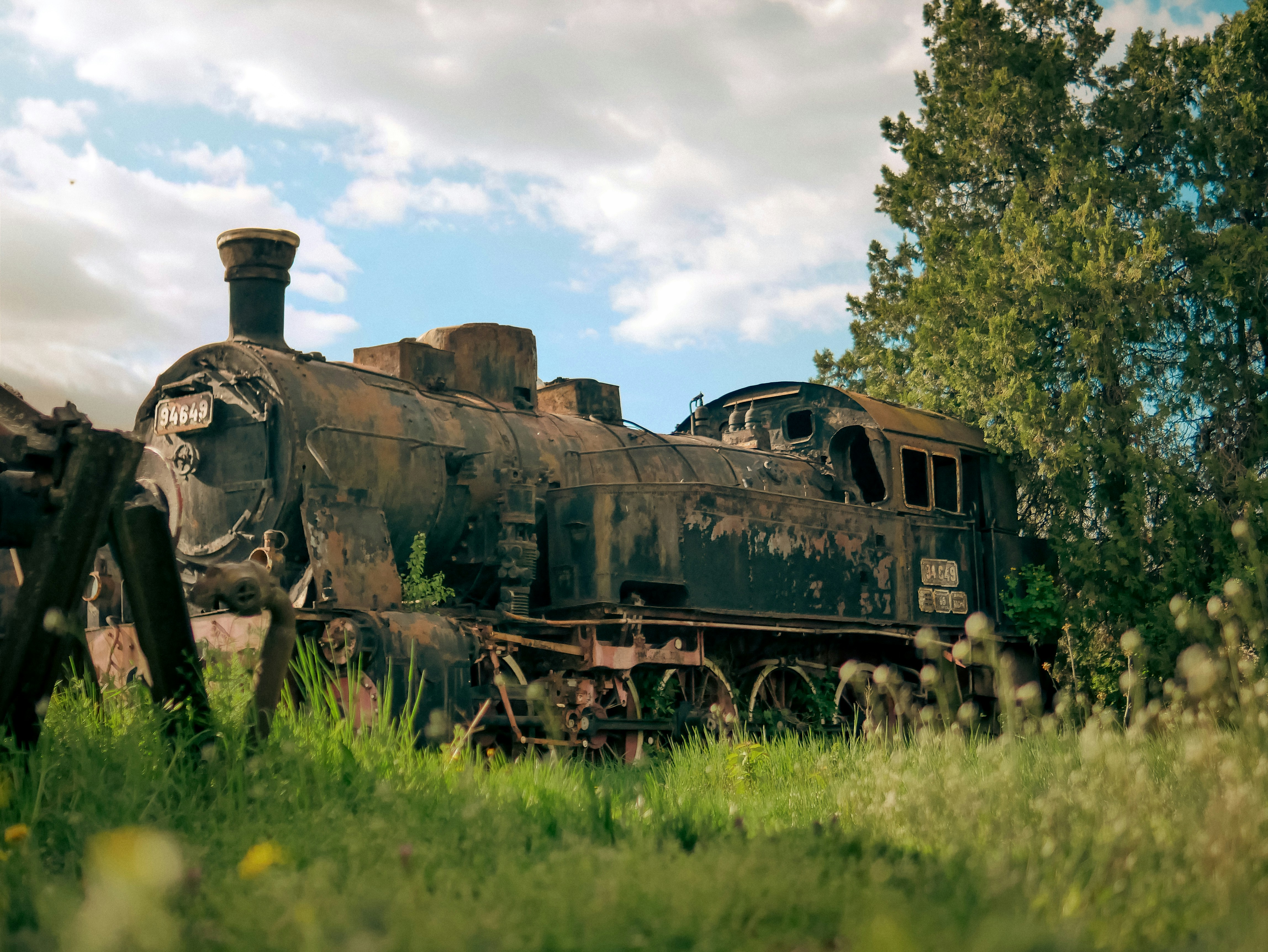 Echoes of Steel: A Rusted Steam Engine Resting in Sunlit Verge