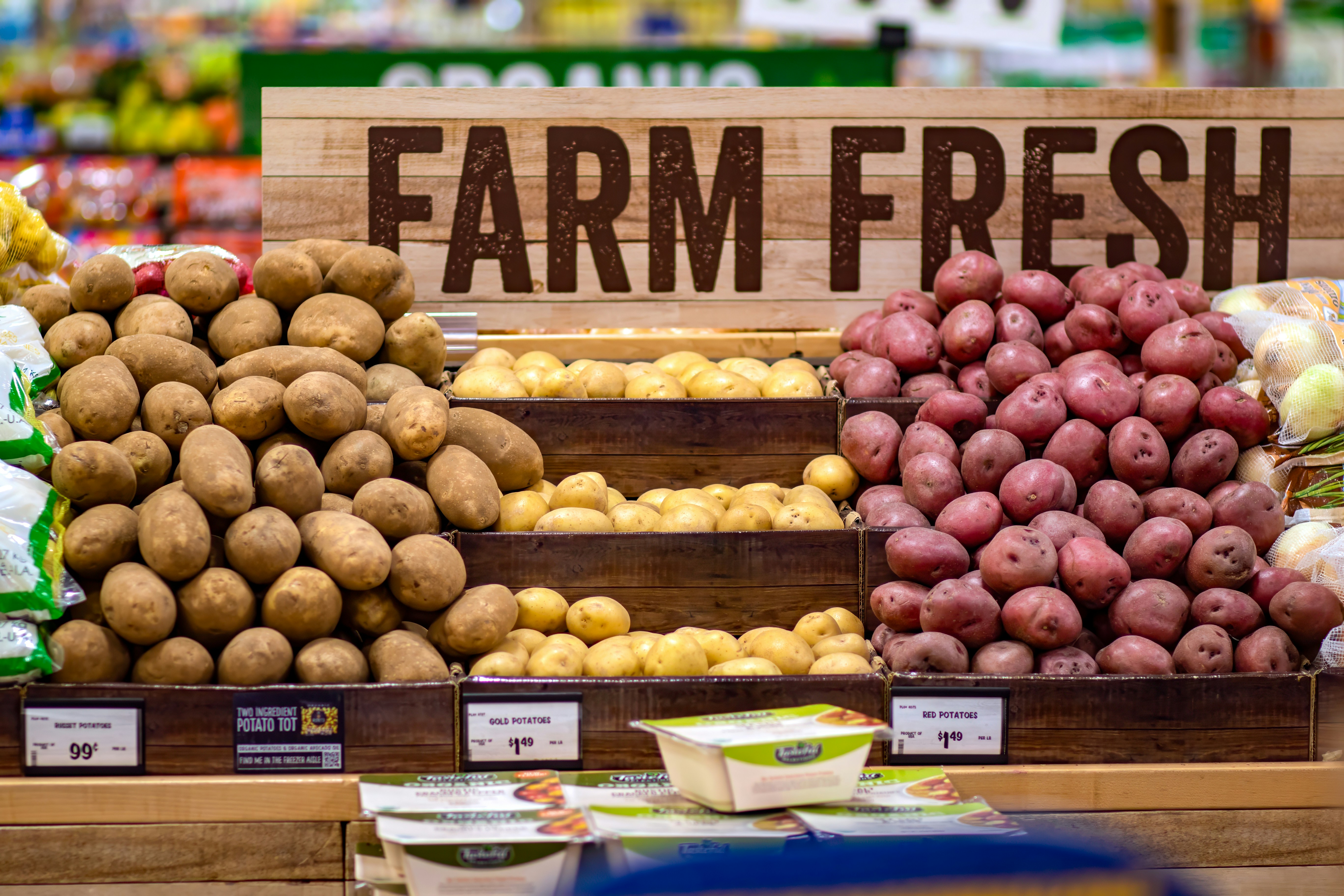 Farm Fresh Produce Display: Potatoes and Onions Framed by a Wooden Sign