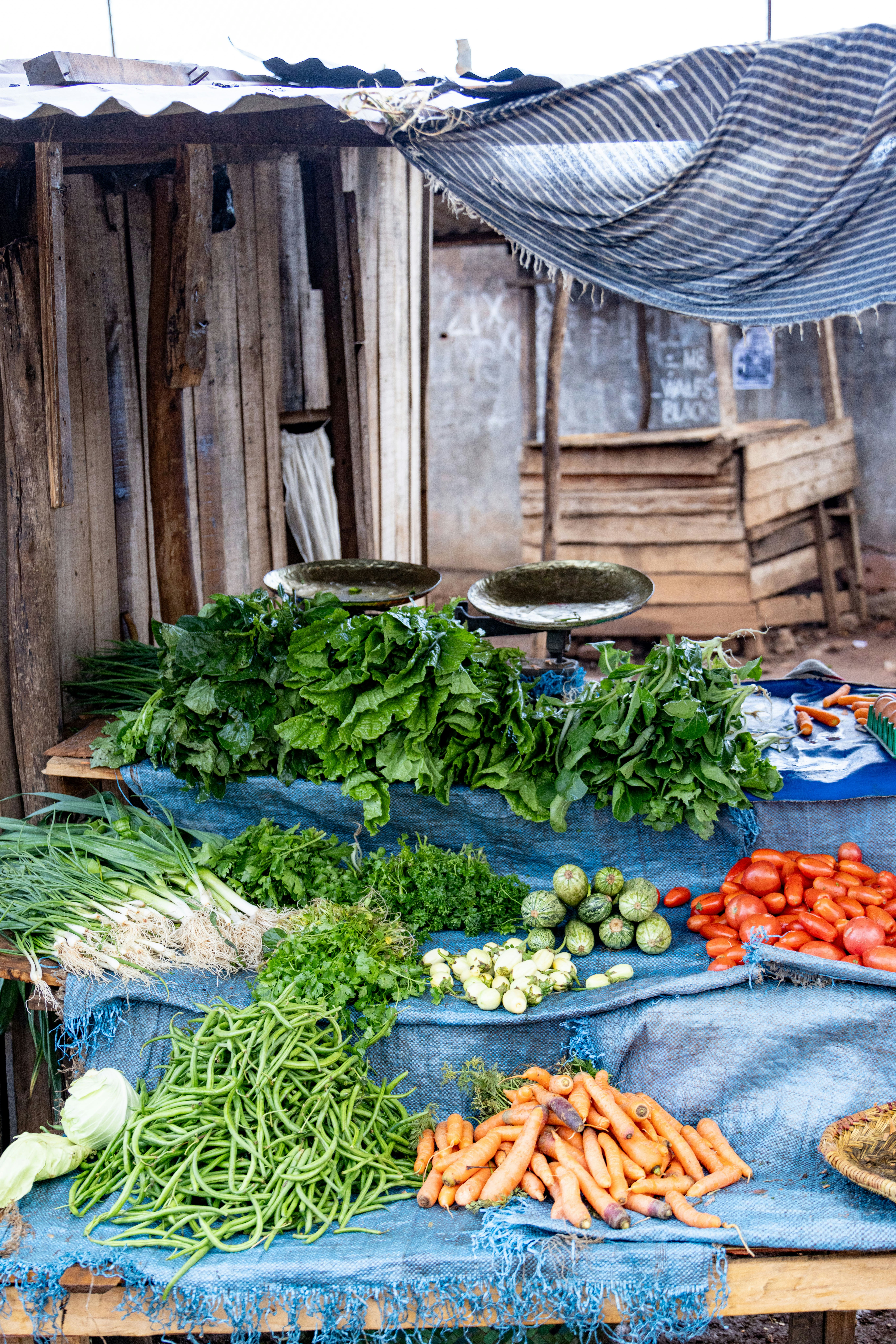 Market Stall Harvest: Fresh Greens and Repacked Vegetables Under a Tarp