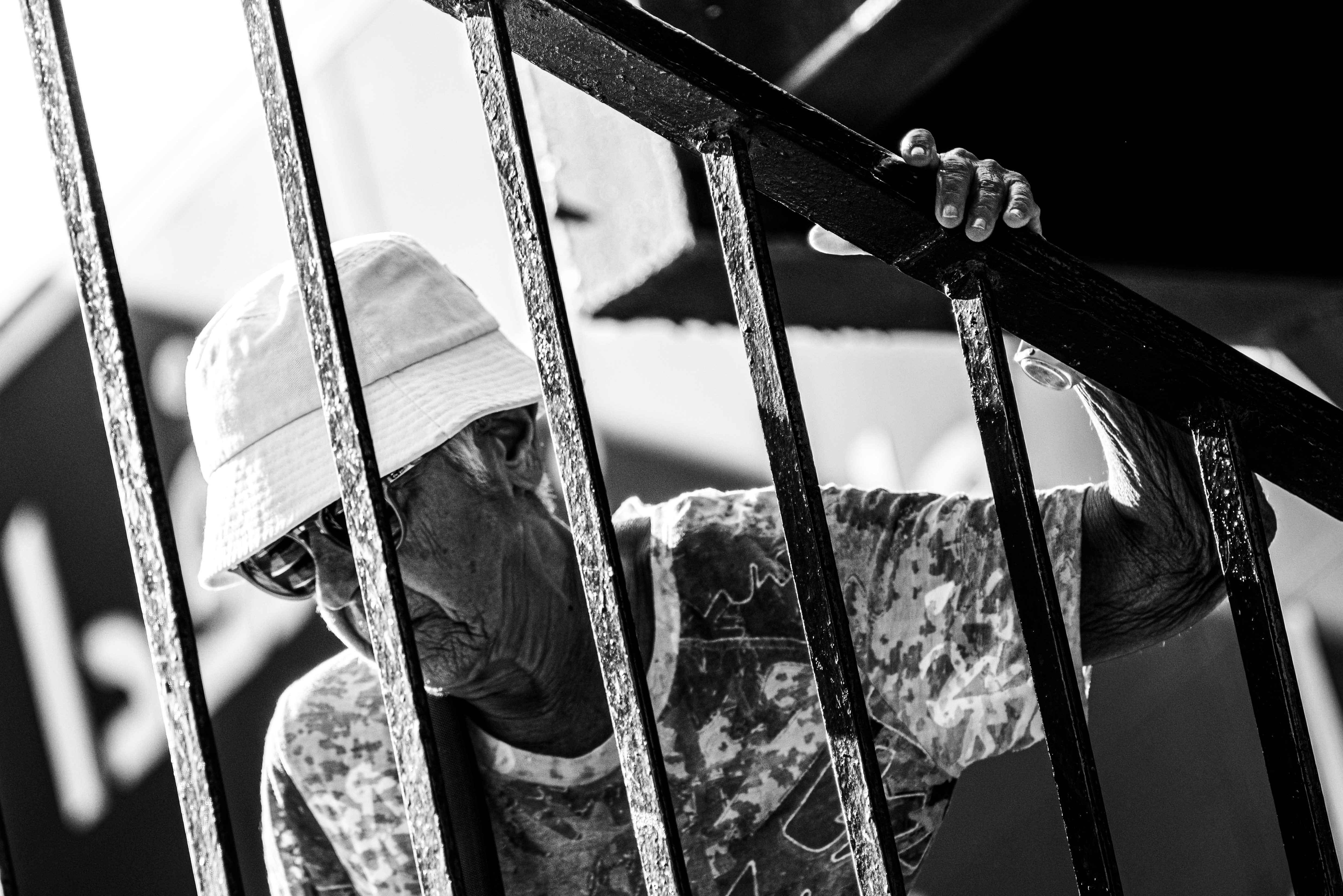 Man on a Weathered Staircase: A Quiet Moment Through Iron Bars