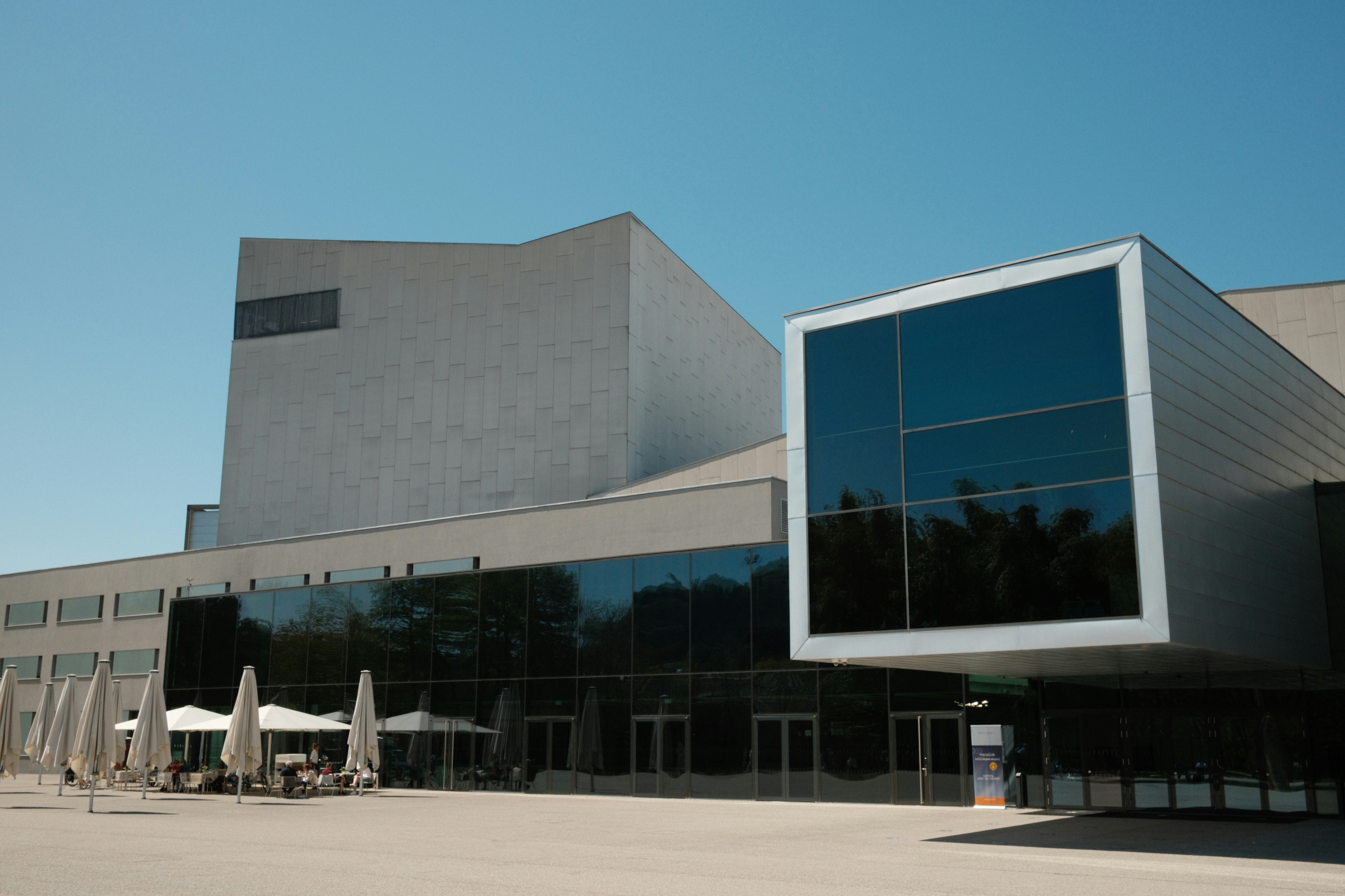 A modern building with large glass windows and outdoor seating.