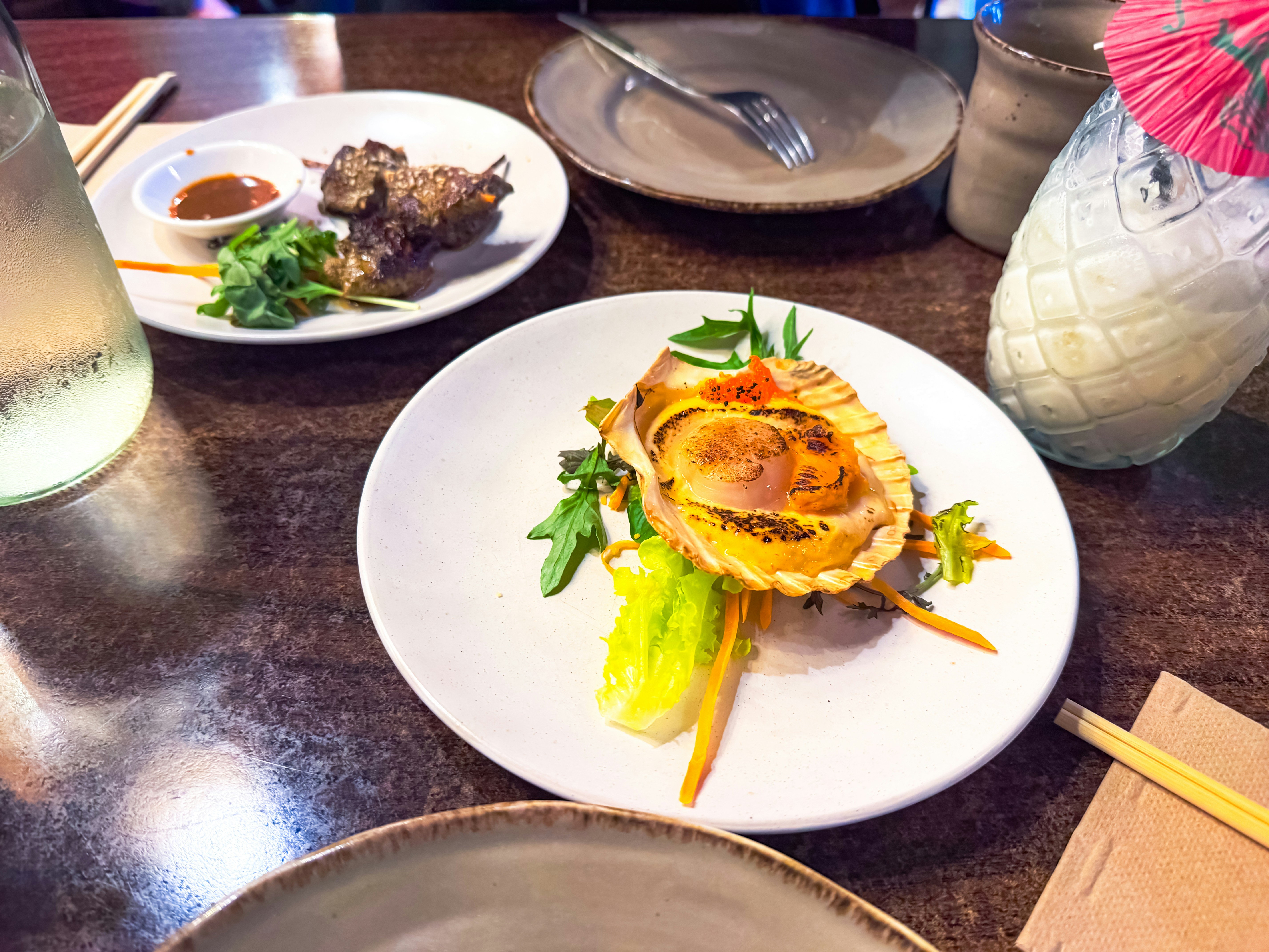 Citrus-glazed scallop on a bed of roast vegetables under a pineapple parasol