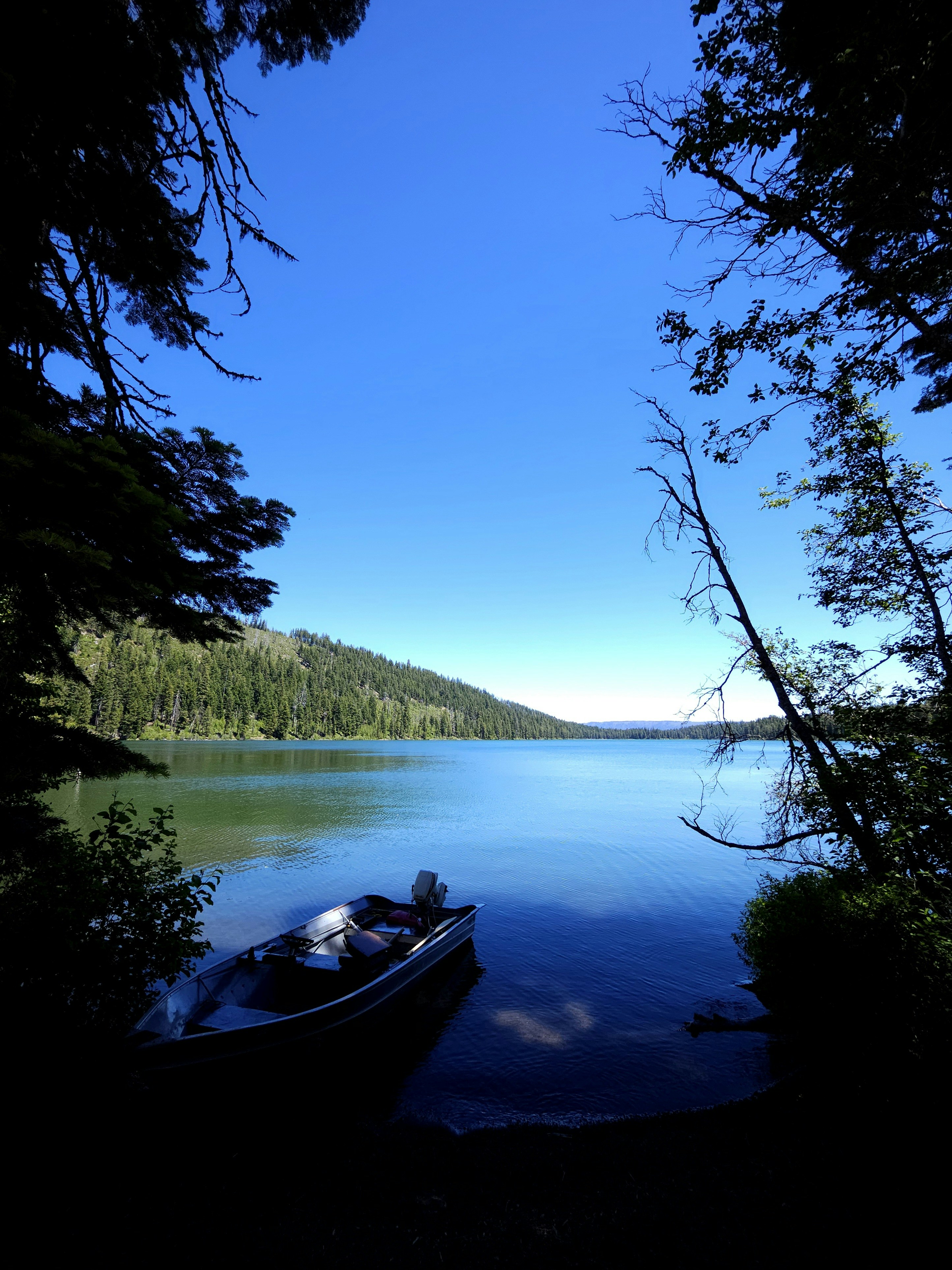 Boat at the Edge of a Quiet Lake Surrounded by Coniferous Hills