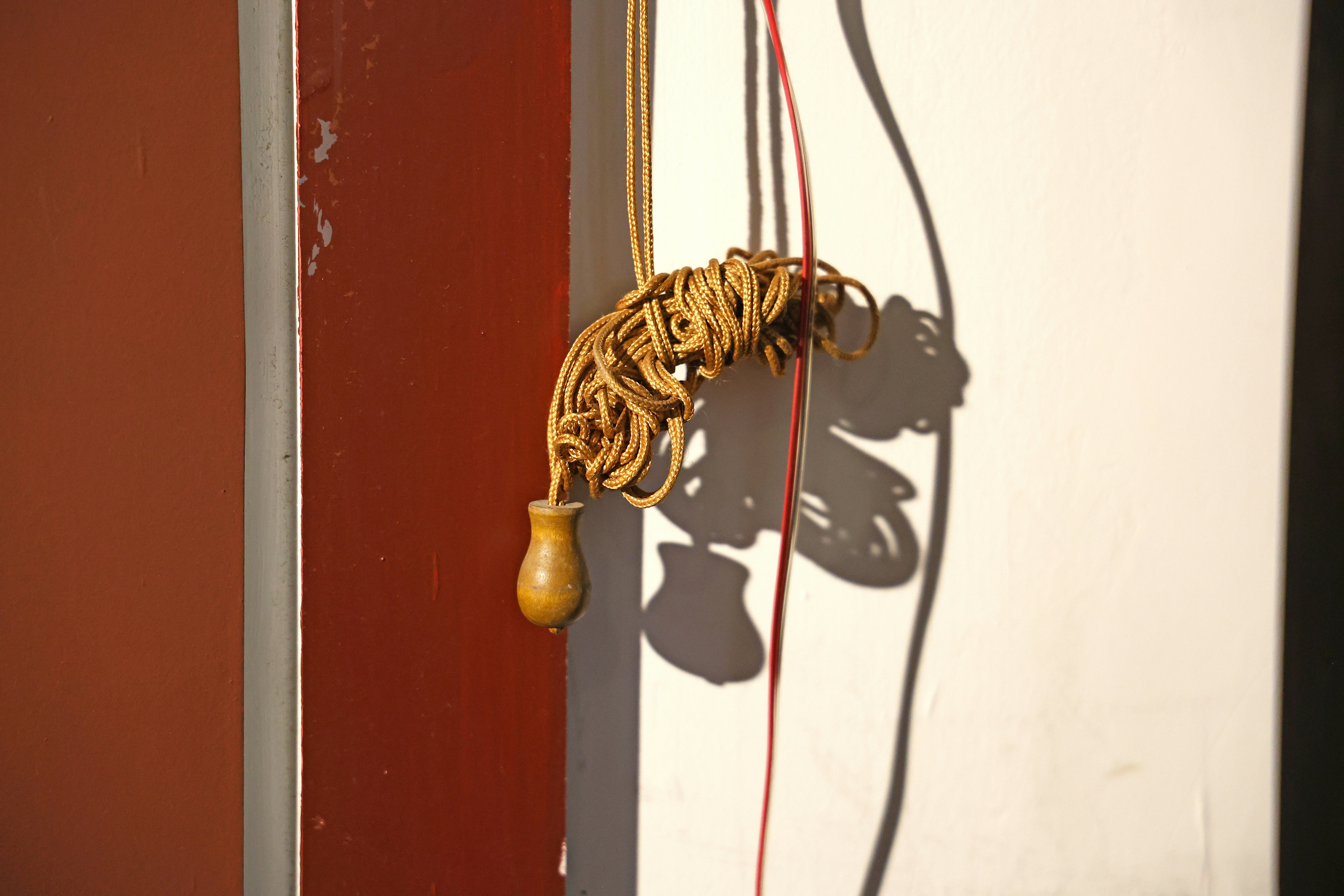 Coiled Rope and Wooden Toggle: Shadowed Details on a Sunlit Wall