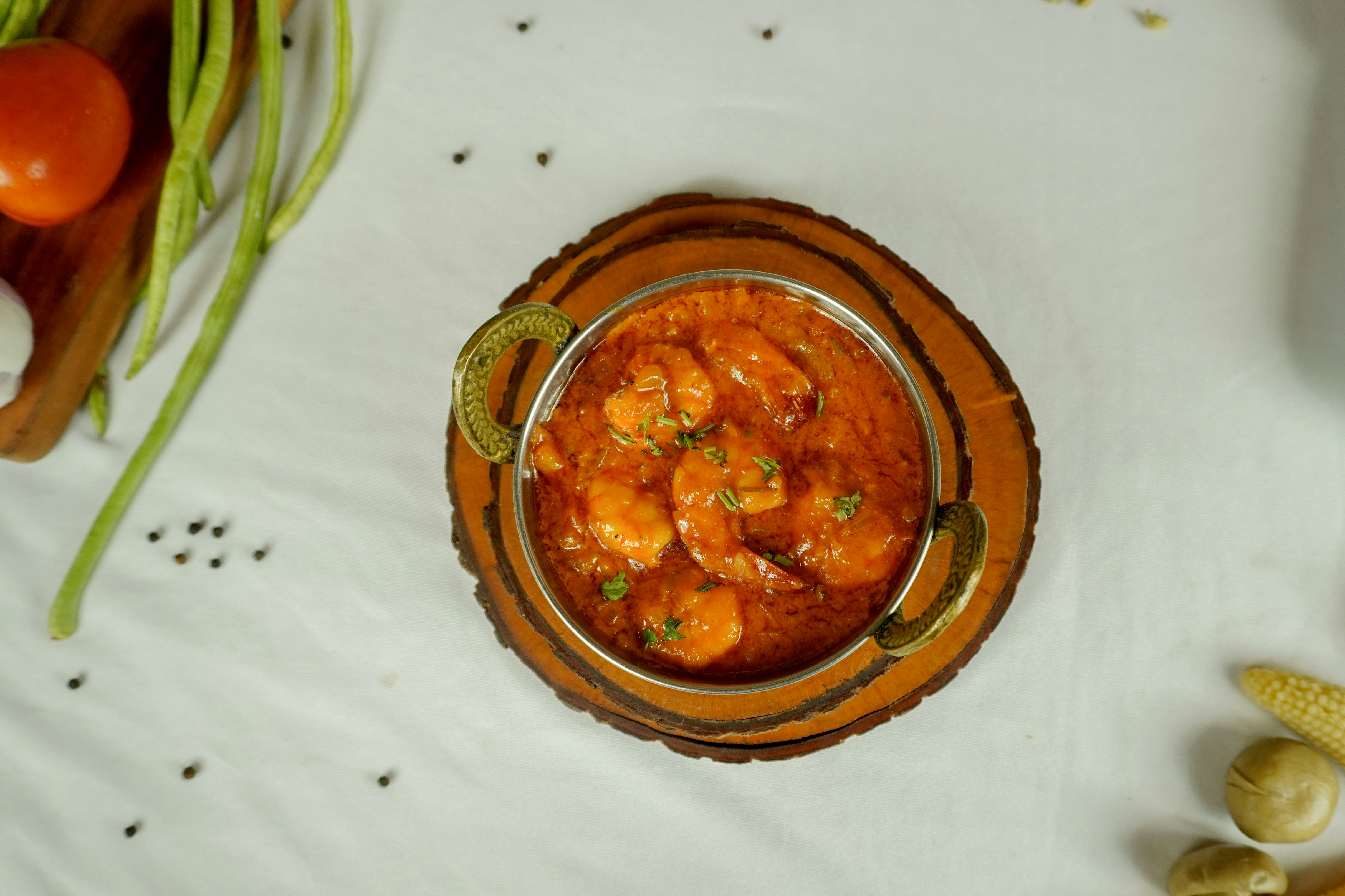 Coppery curry in a round copper dish tucked on a white linen backdrop