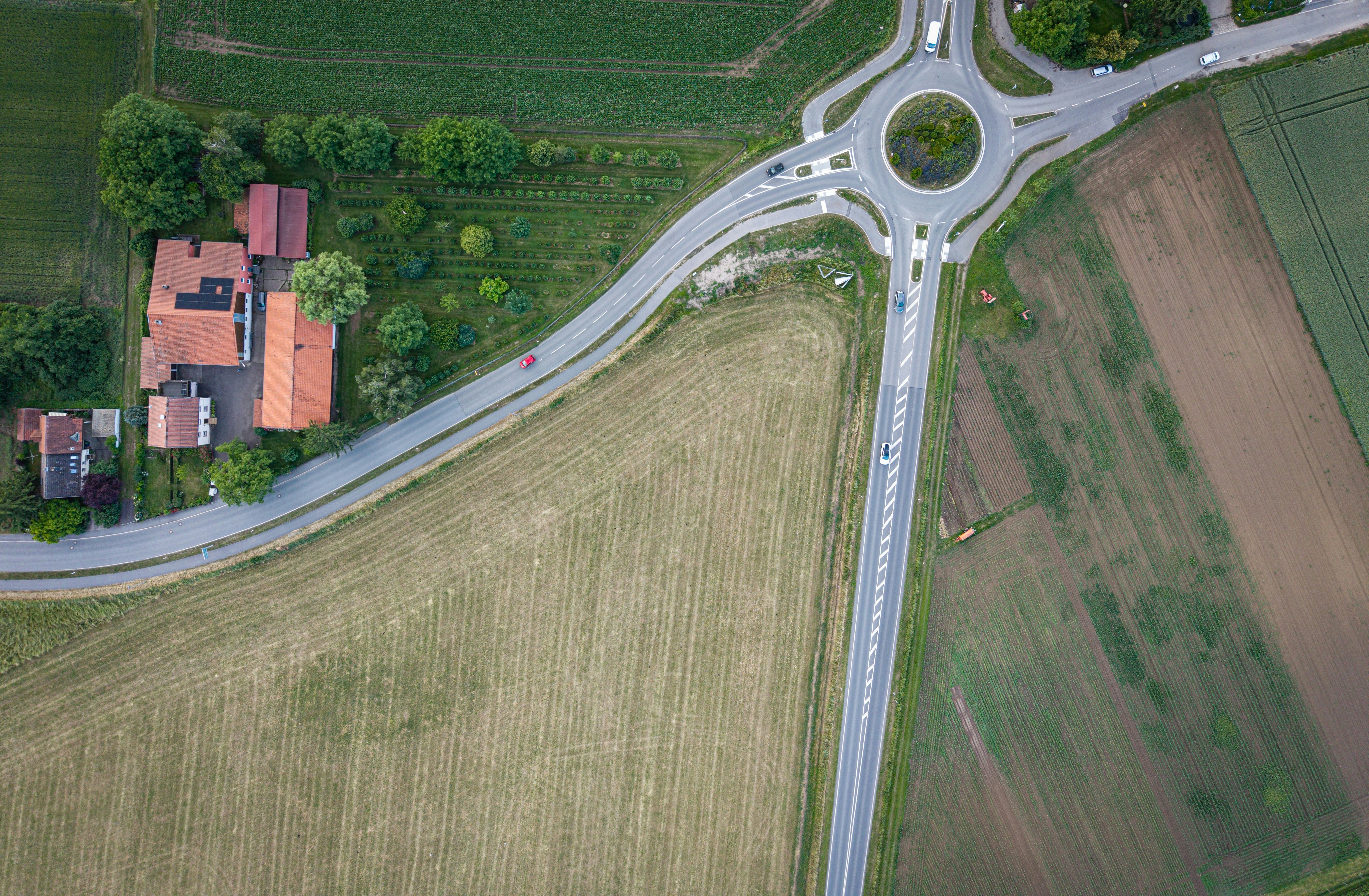 Aerial view of a rural roundabout, fields, and houses.