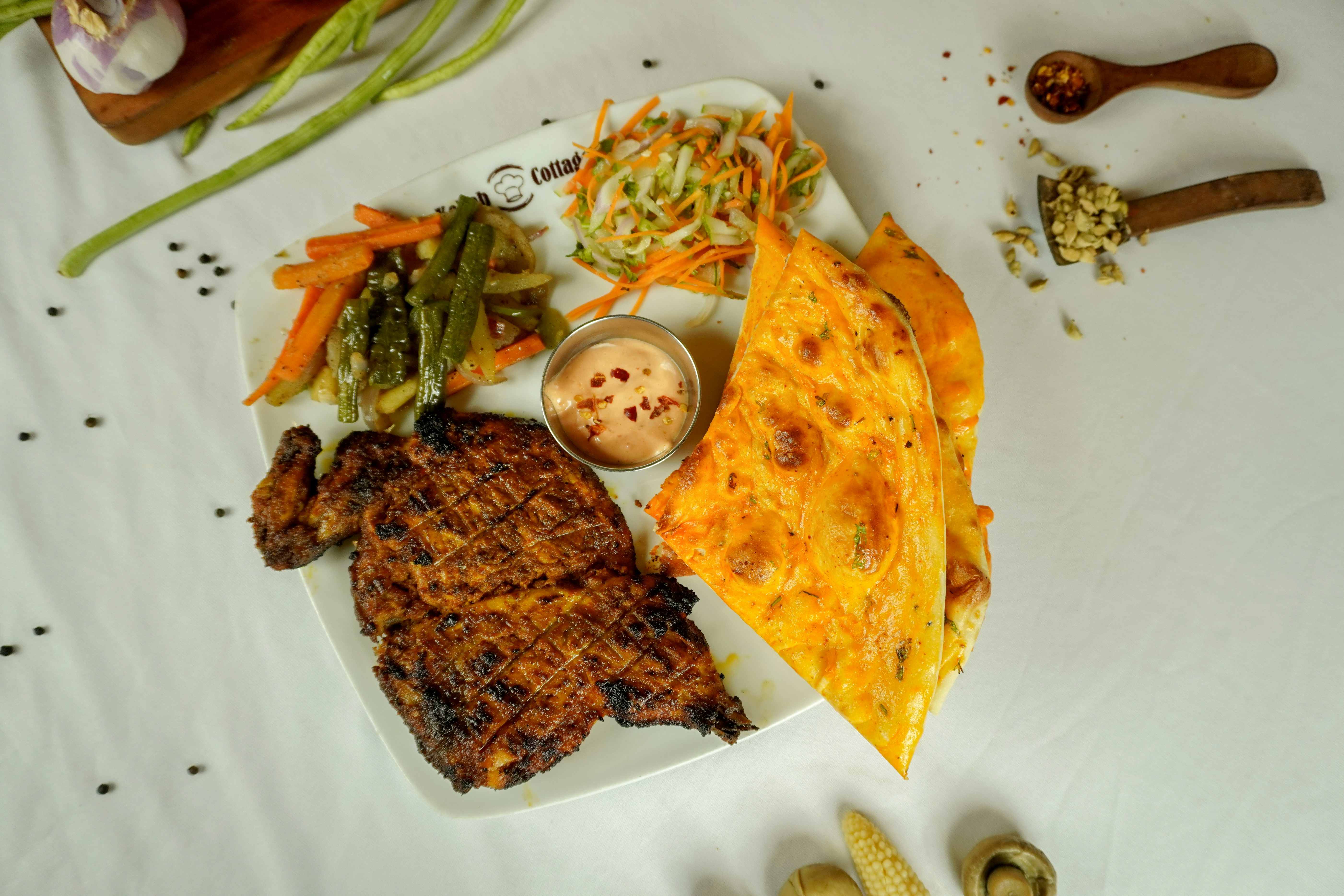 Grilled steak, flatbread and slaw on a white table with spices