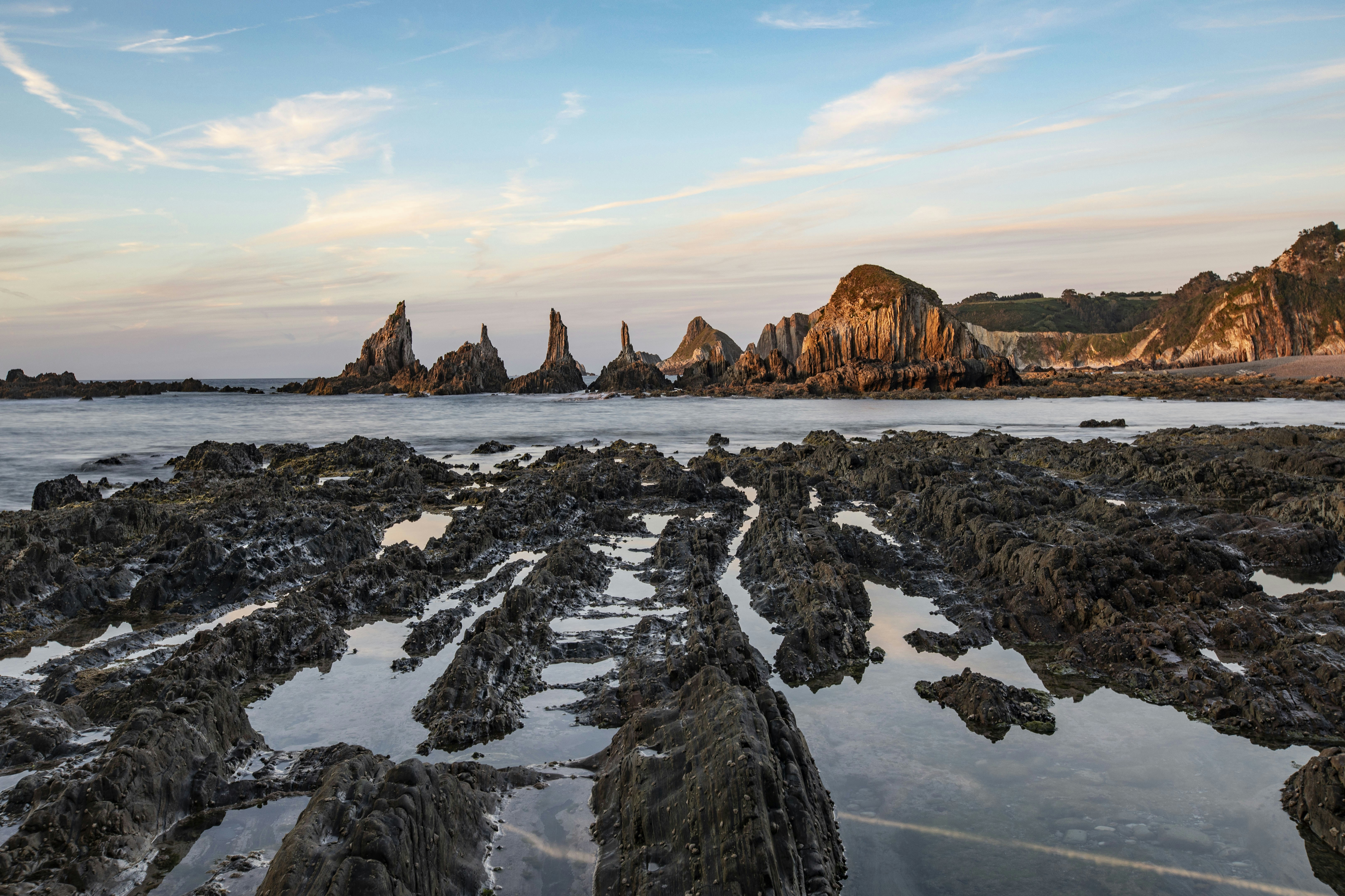 Rock-tongued shoreline under a pastel sky at sunset
