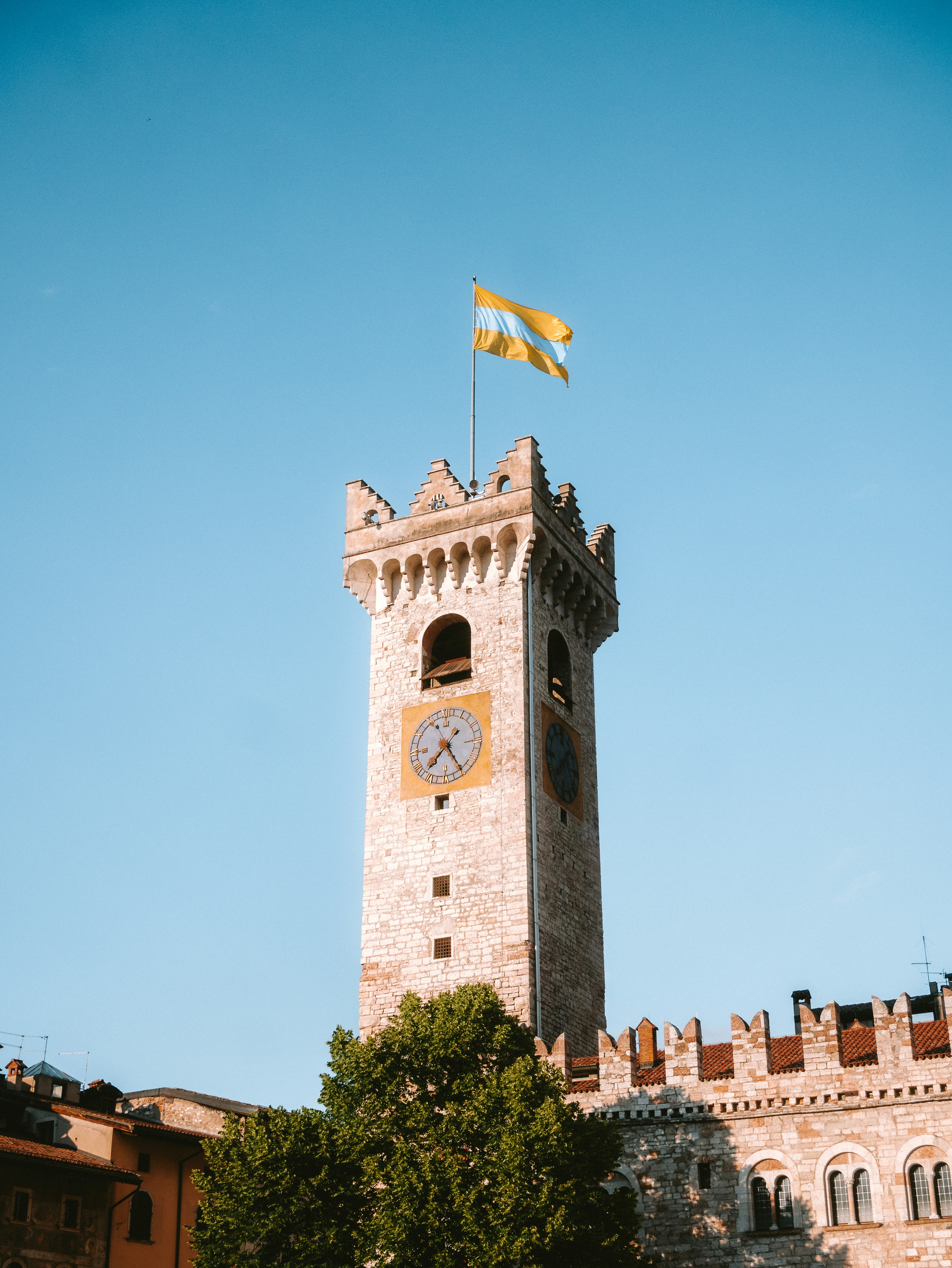 Historic stone clock tower with flag under clear sky.