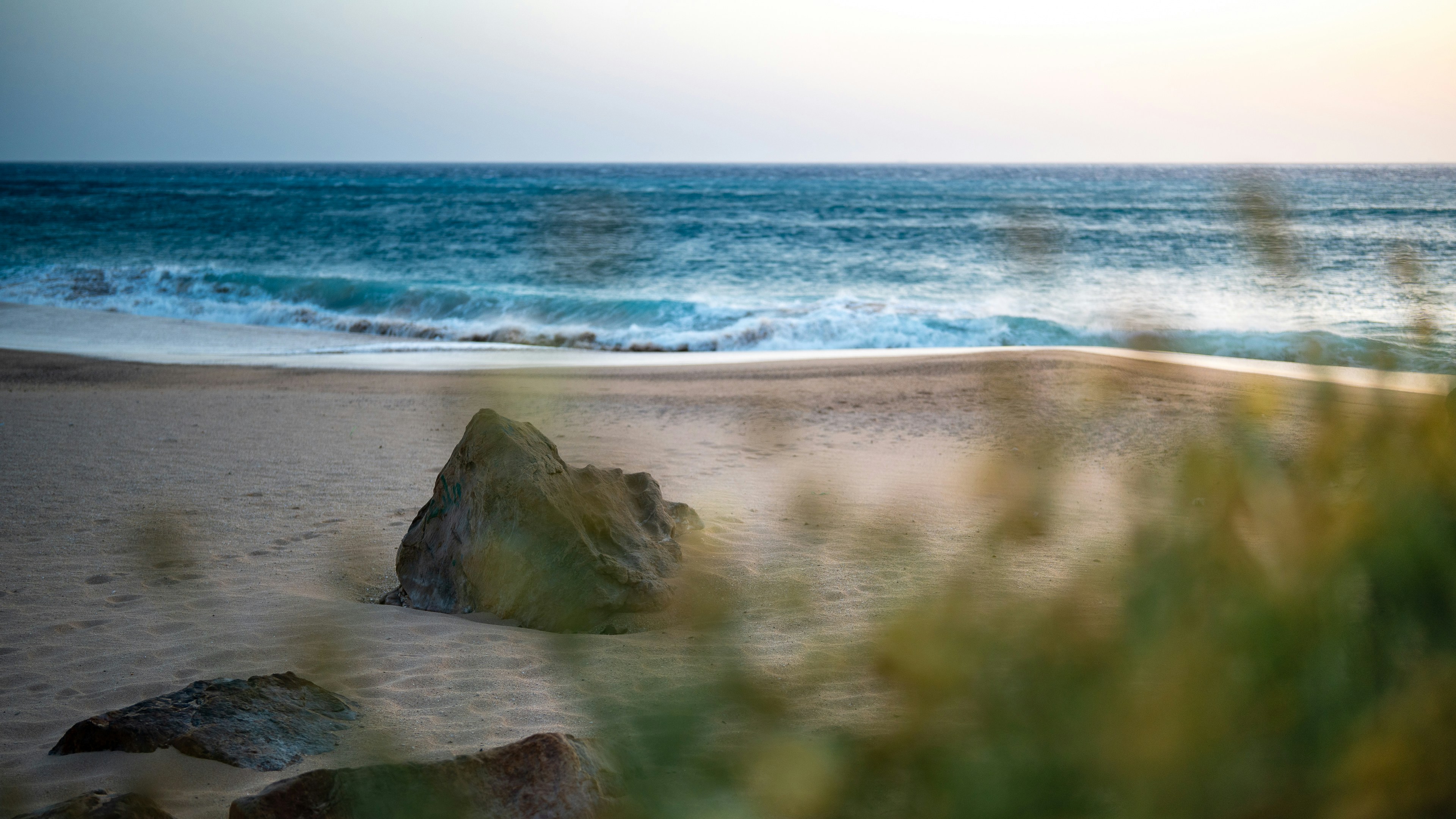 Quiet Shoreline Fragment: Sand, Rock, and Distant Surf