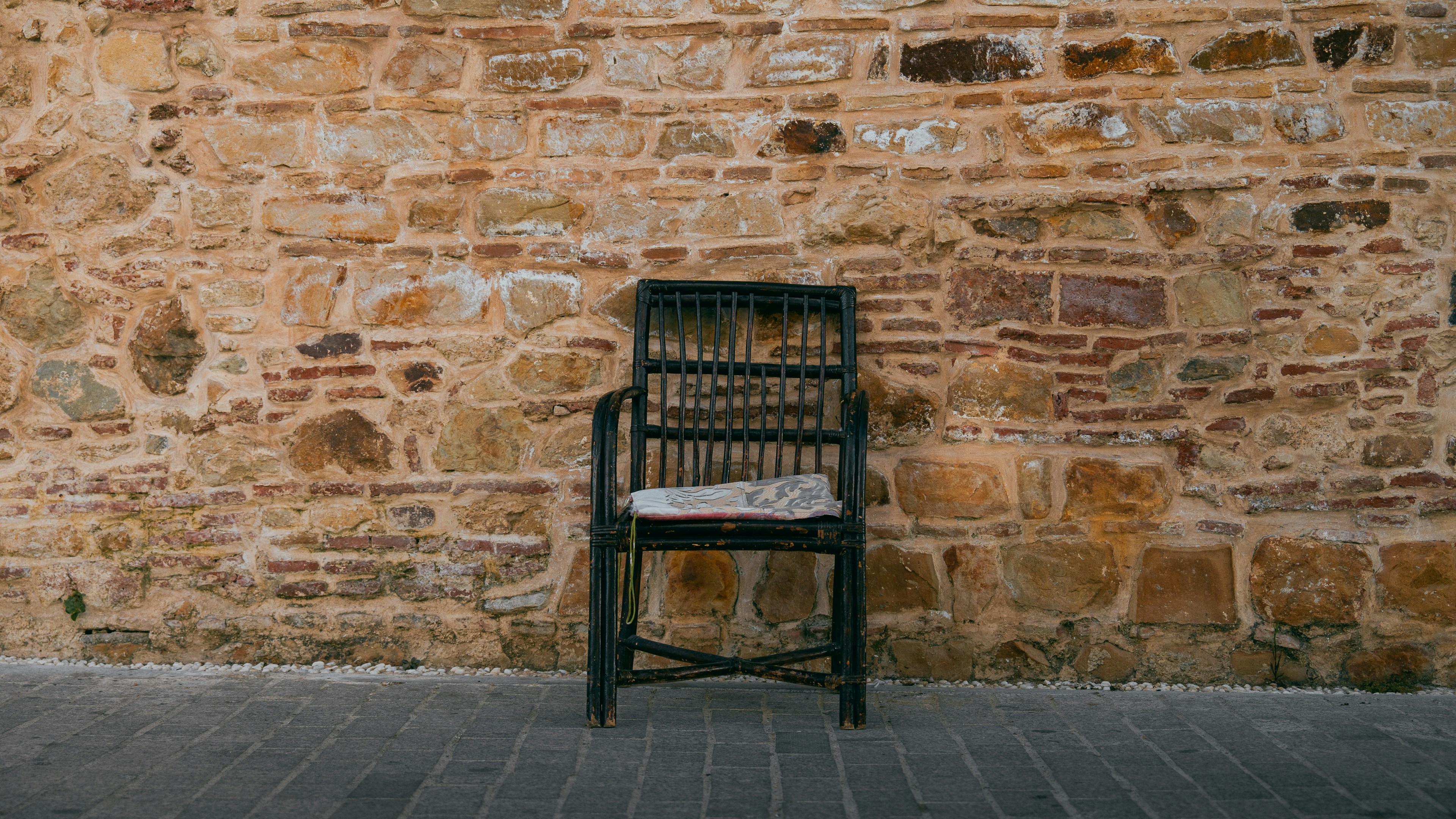 Solitary chair against weathered brick: still life in a street rubato