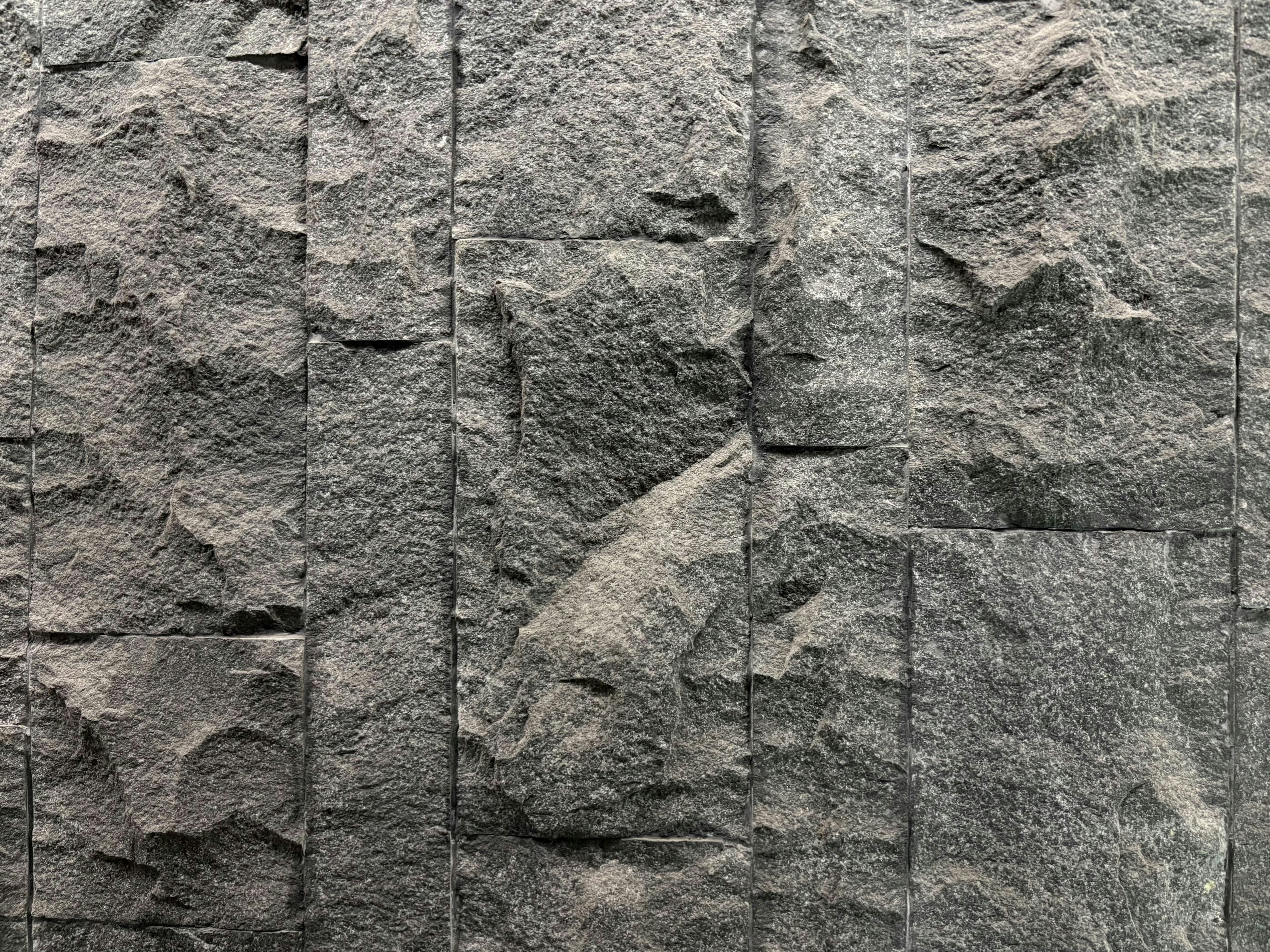 Rough dark grey stone wall with textured surface.