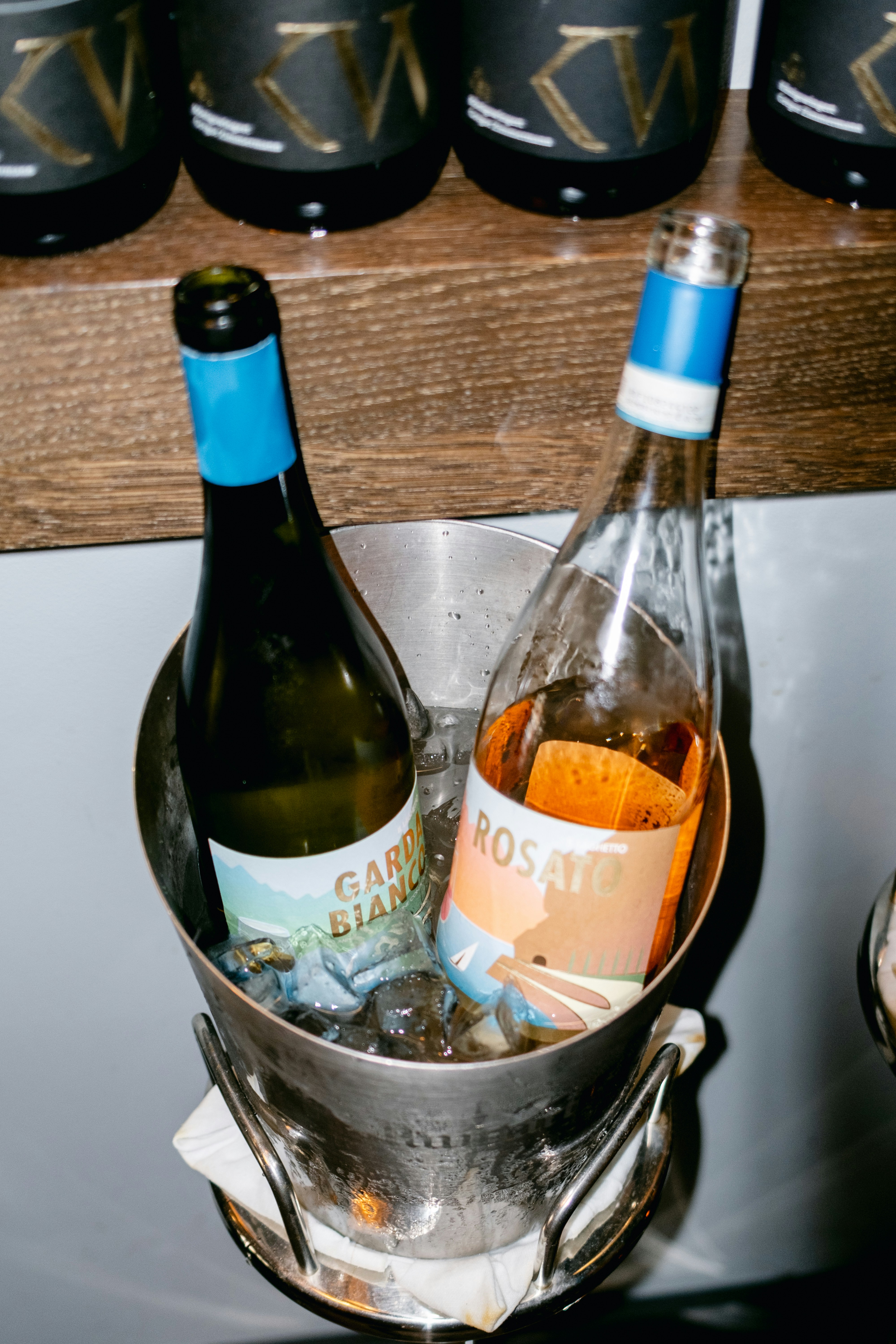White and rosé wine bottles in a metal ice bucket.