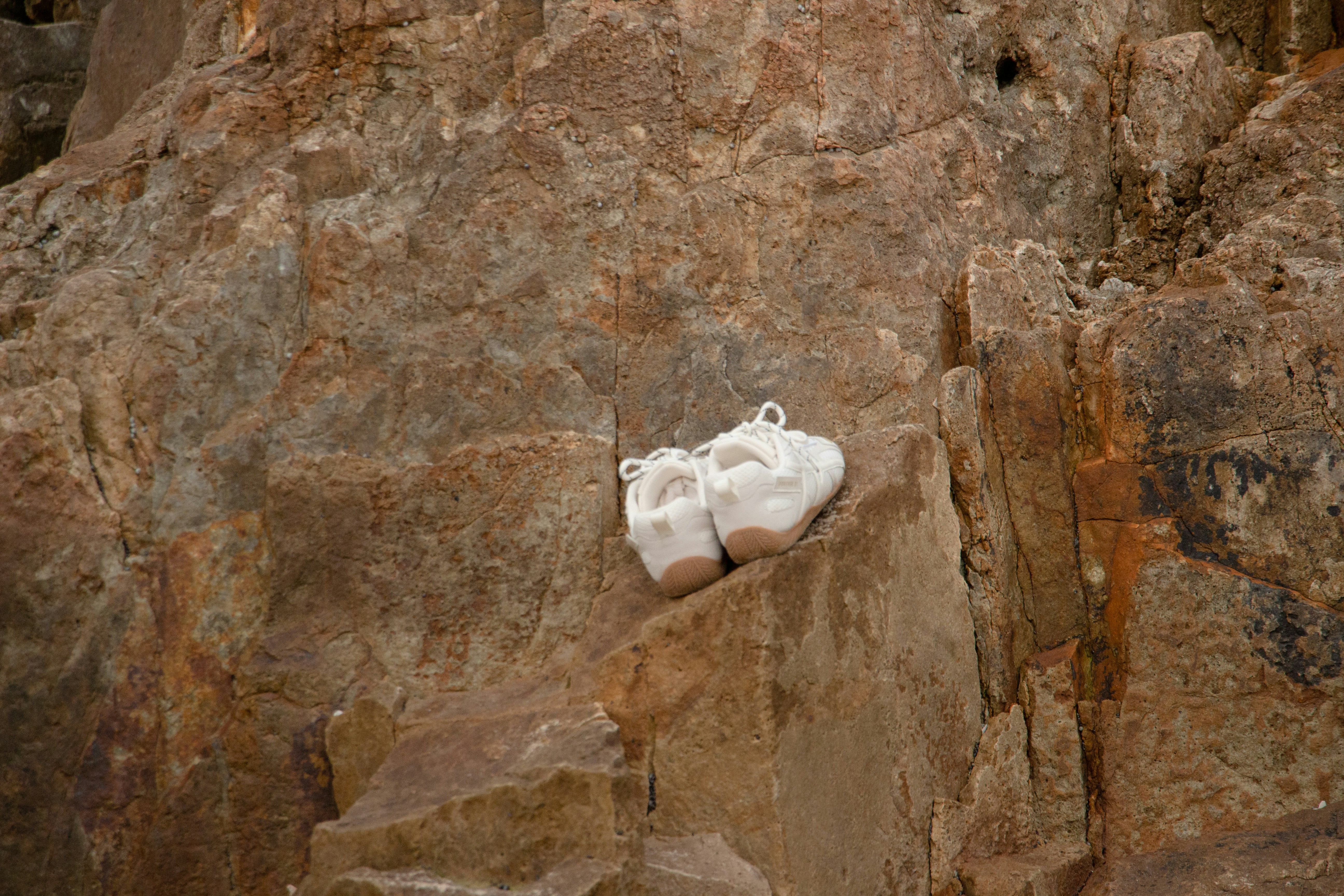 White sneakers wedged on rugged cliff face