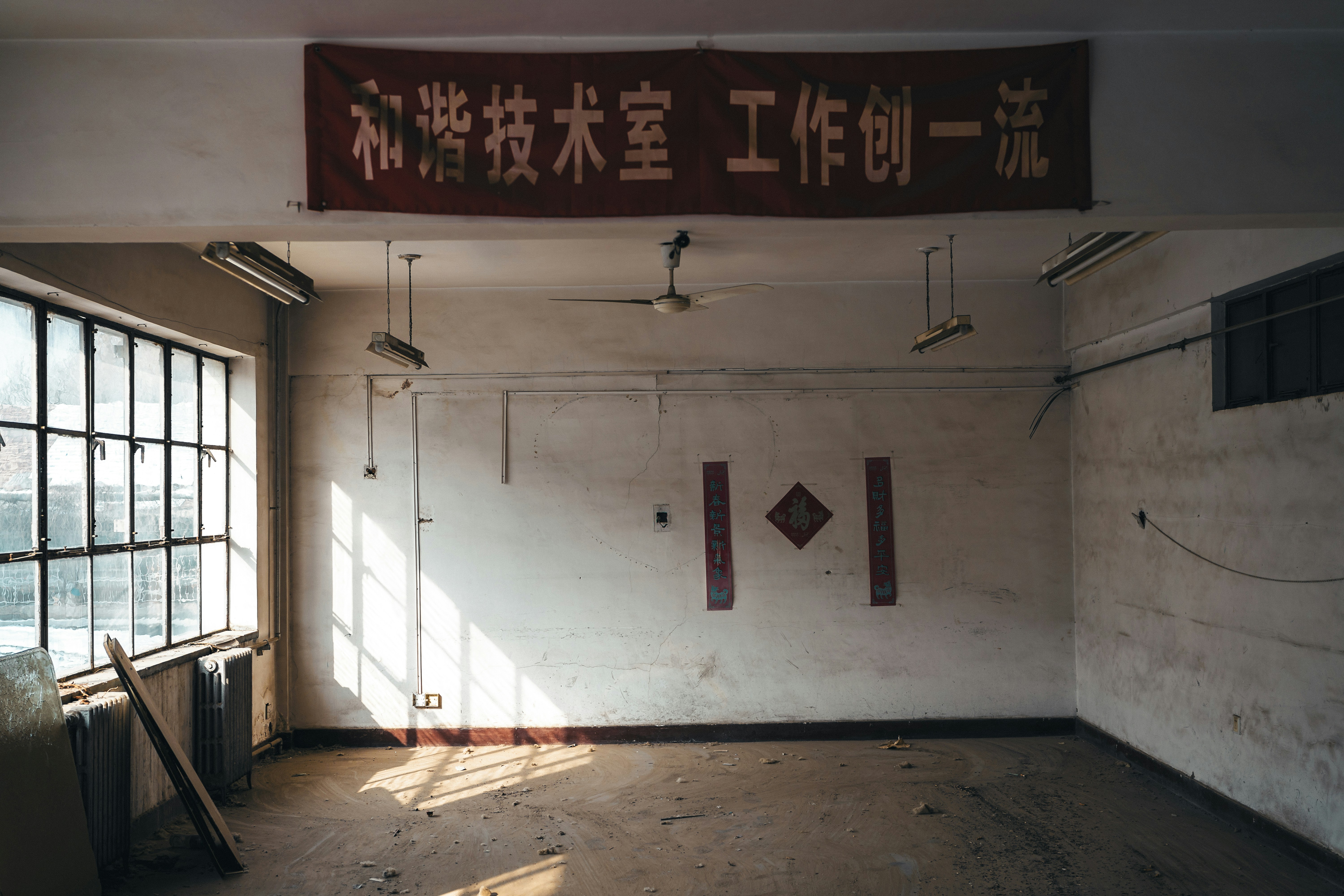 Sunlit, empty room with a red banner and wall symbol.