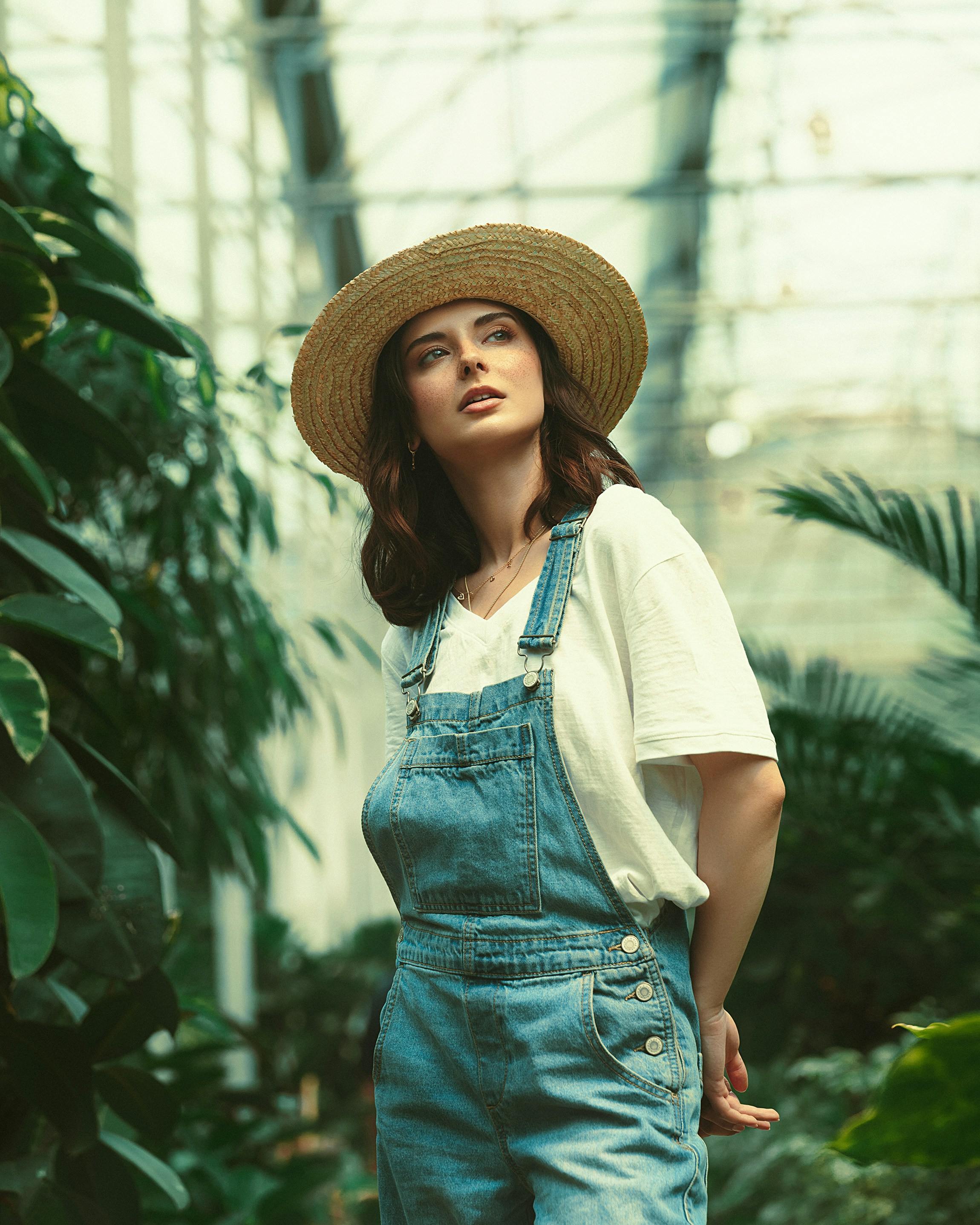 Young woman wearing a straw hat among green plants.