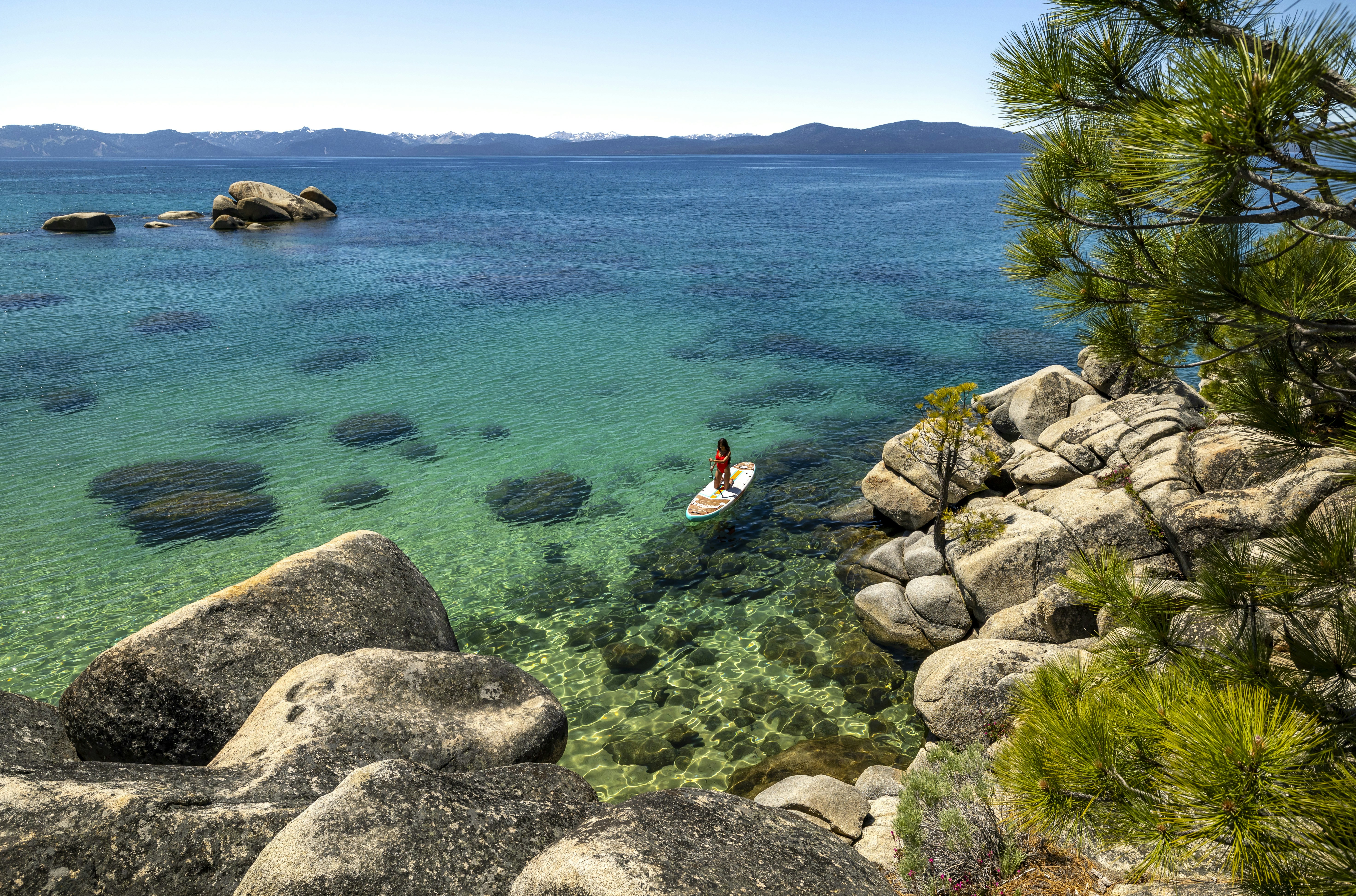 Silent Paddle: A lone surfer glides along crystal-green shores