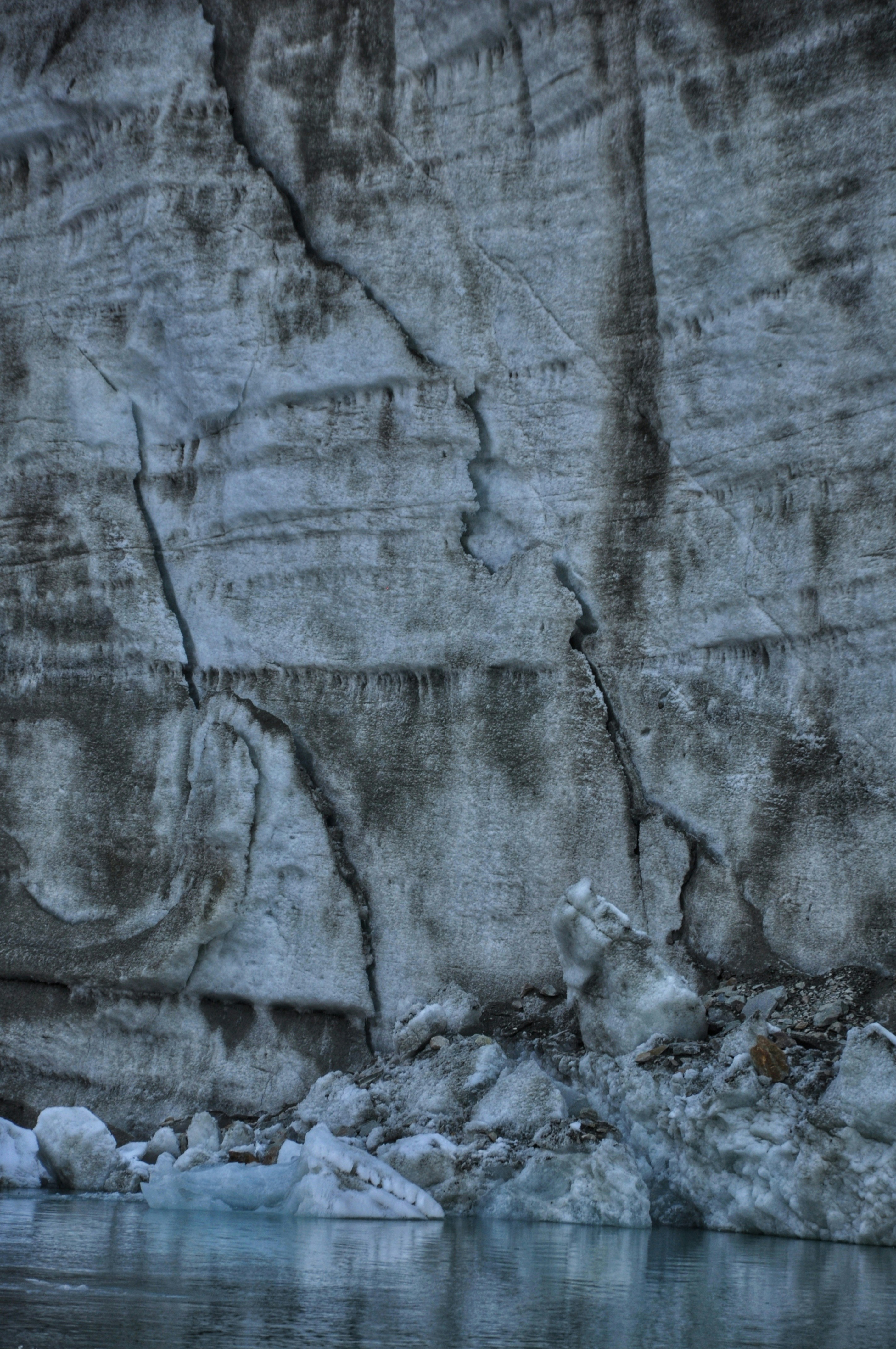 Cracked glacier face descends into calm glacial water.