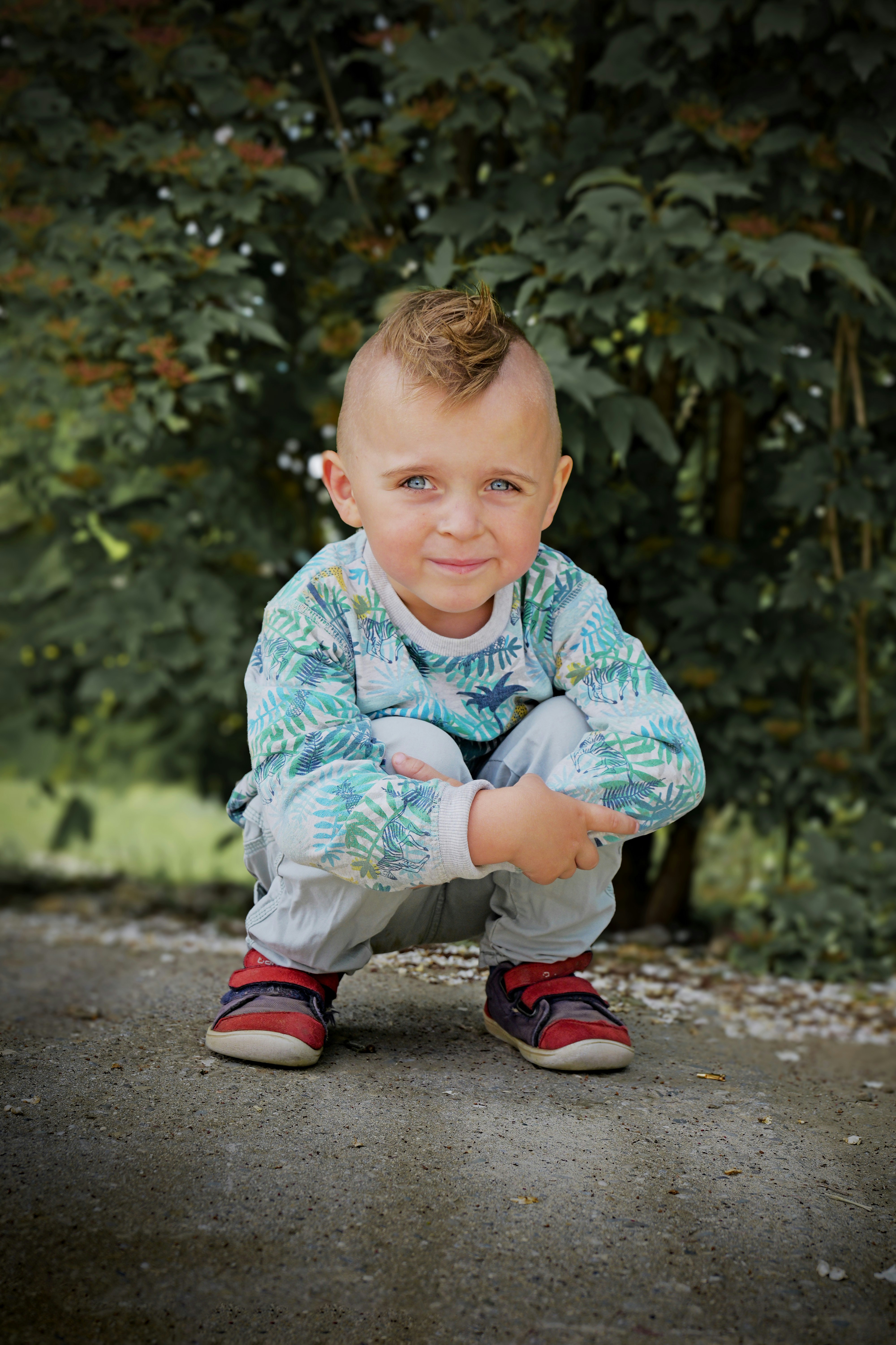 Squat to Smile: A Curious Toddler Under Green Canopy
