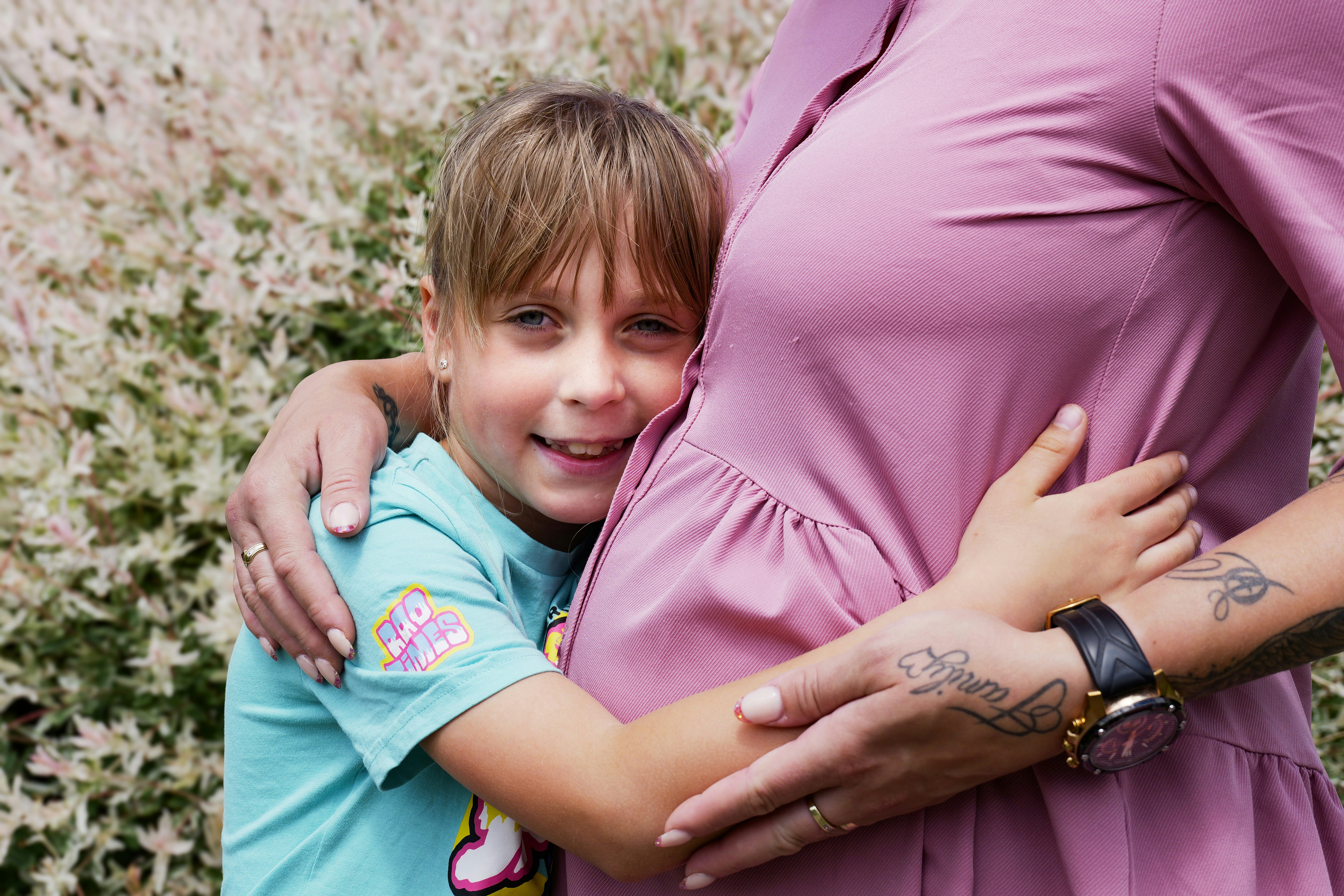 Happy child embracing a pregnant woman's belly.