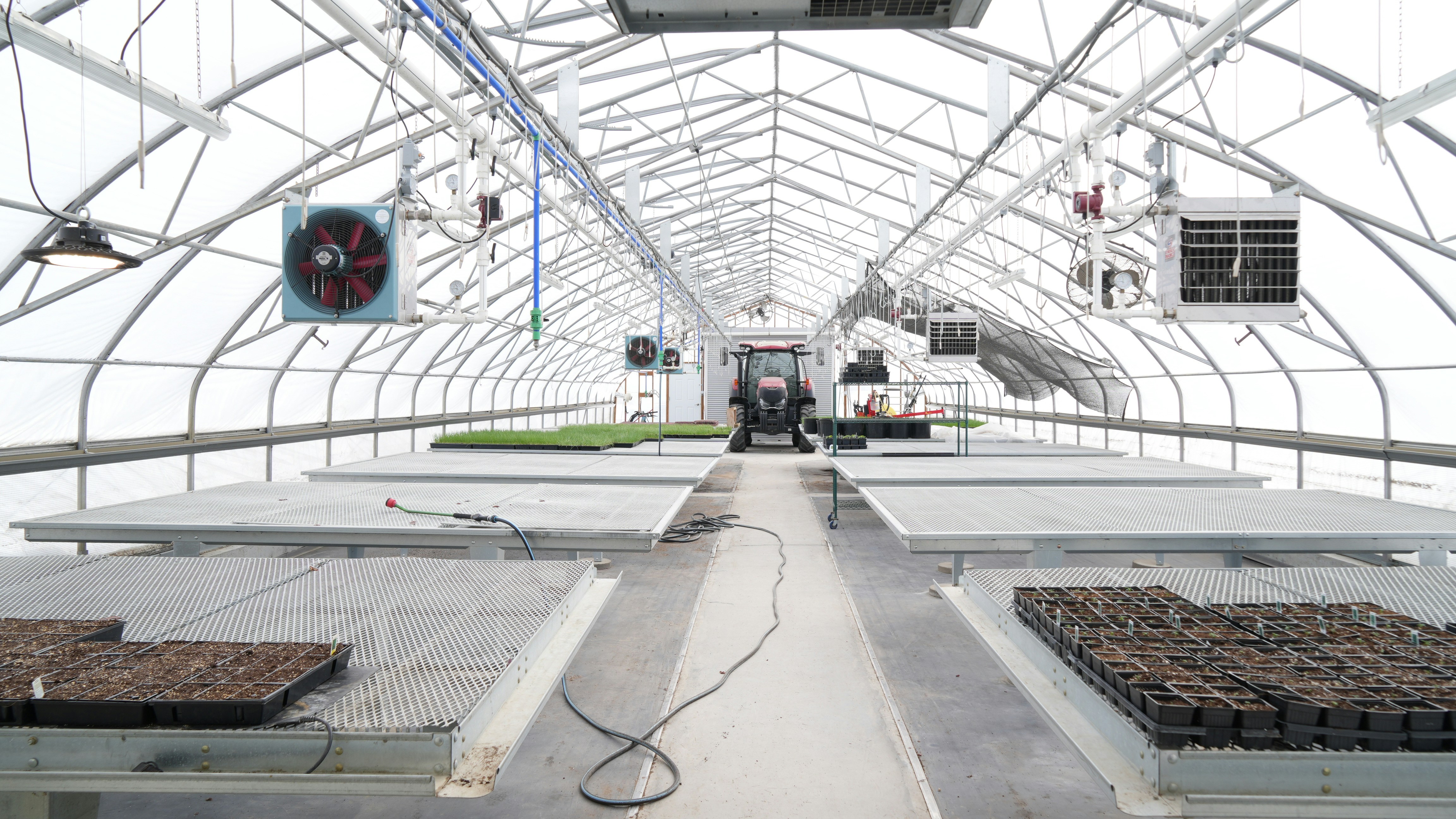 Inside the Glasshouse: Rows of Seedlings and Machinery in a High-Tech Tunnel