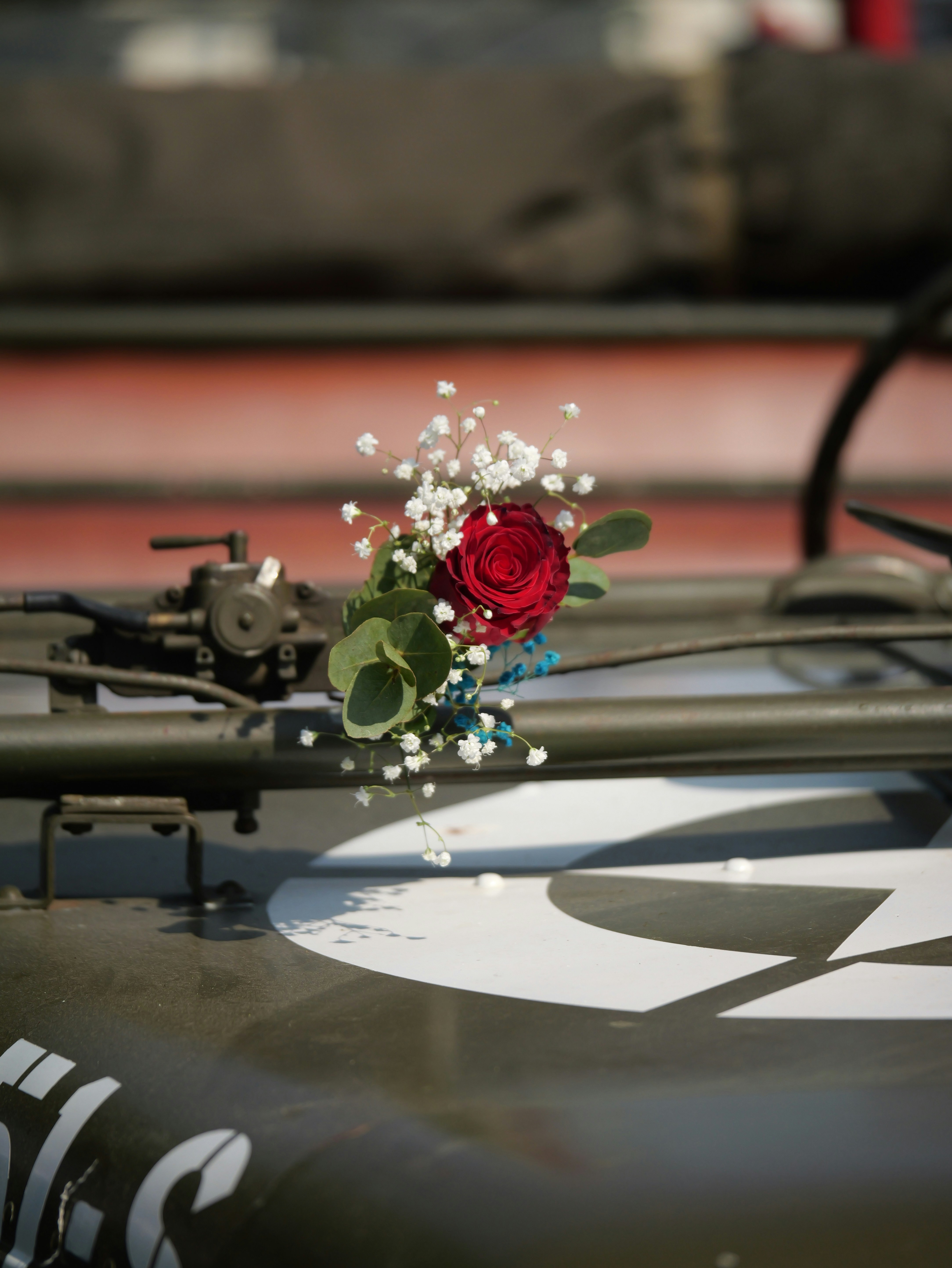 A red rose and baby's breath on a military vehicle.