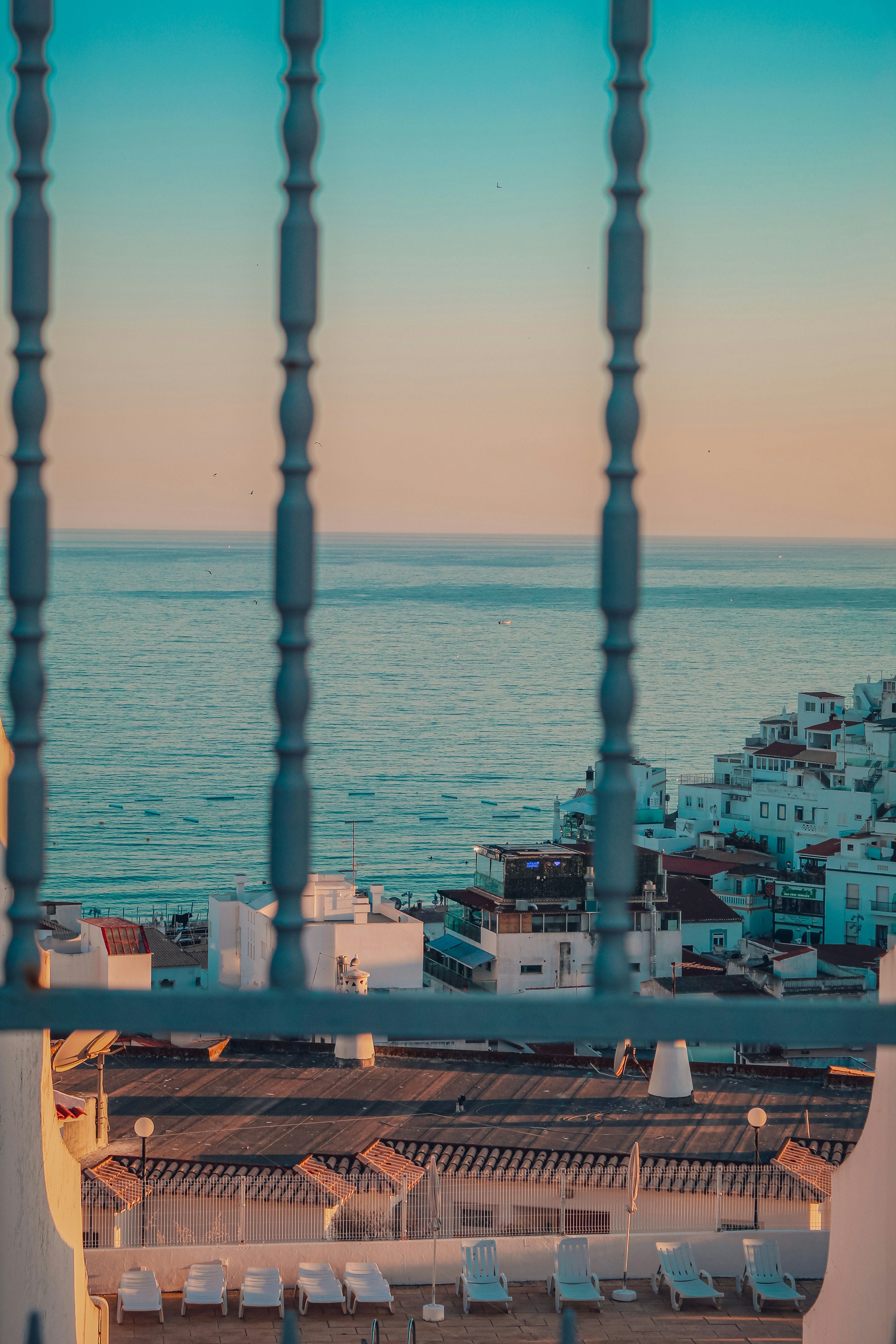 Sea View Between Carved Balusters: Sunset Over a Coastal Town