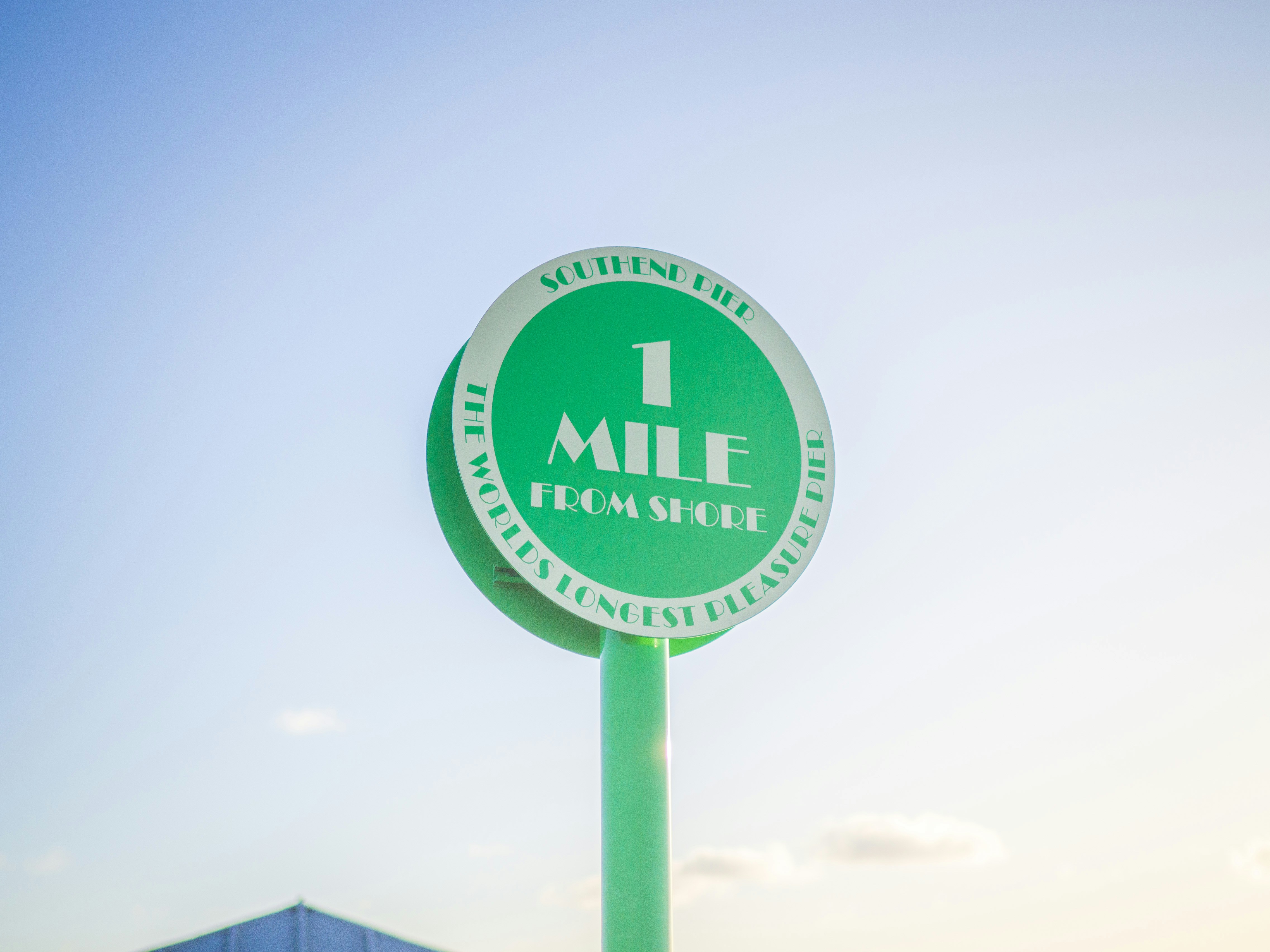 Green 1 Mile Sign Stemming from Shore Over a Bright Sky