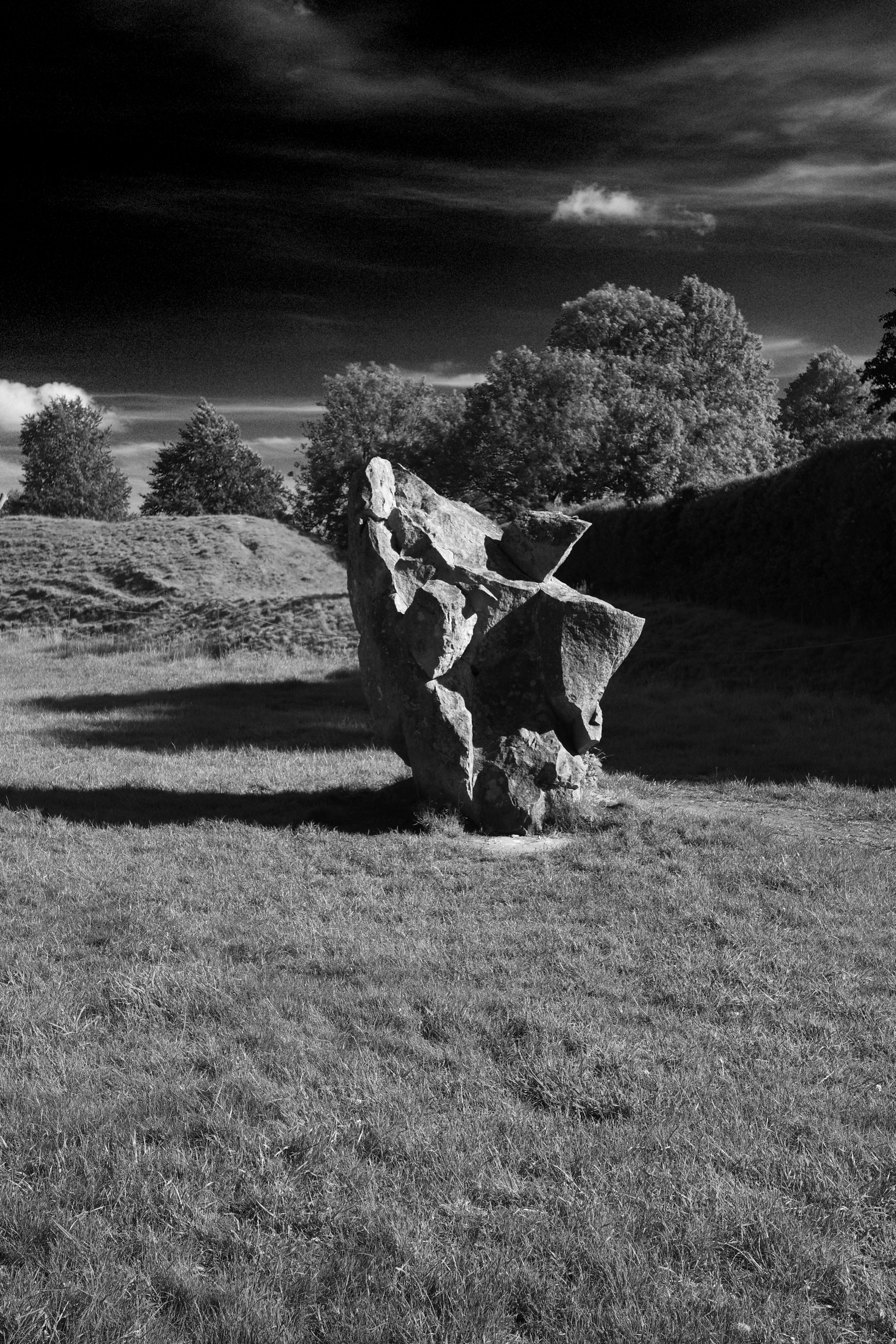Dramatic black and white landscape with a large standing stone.