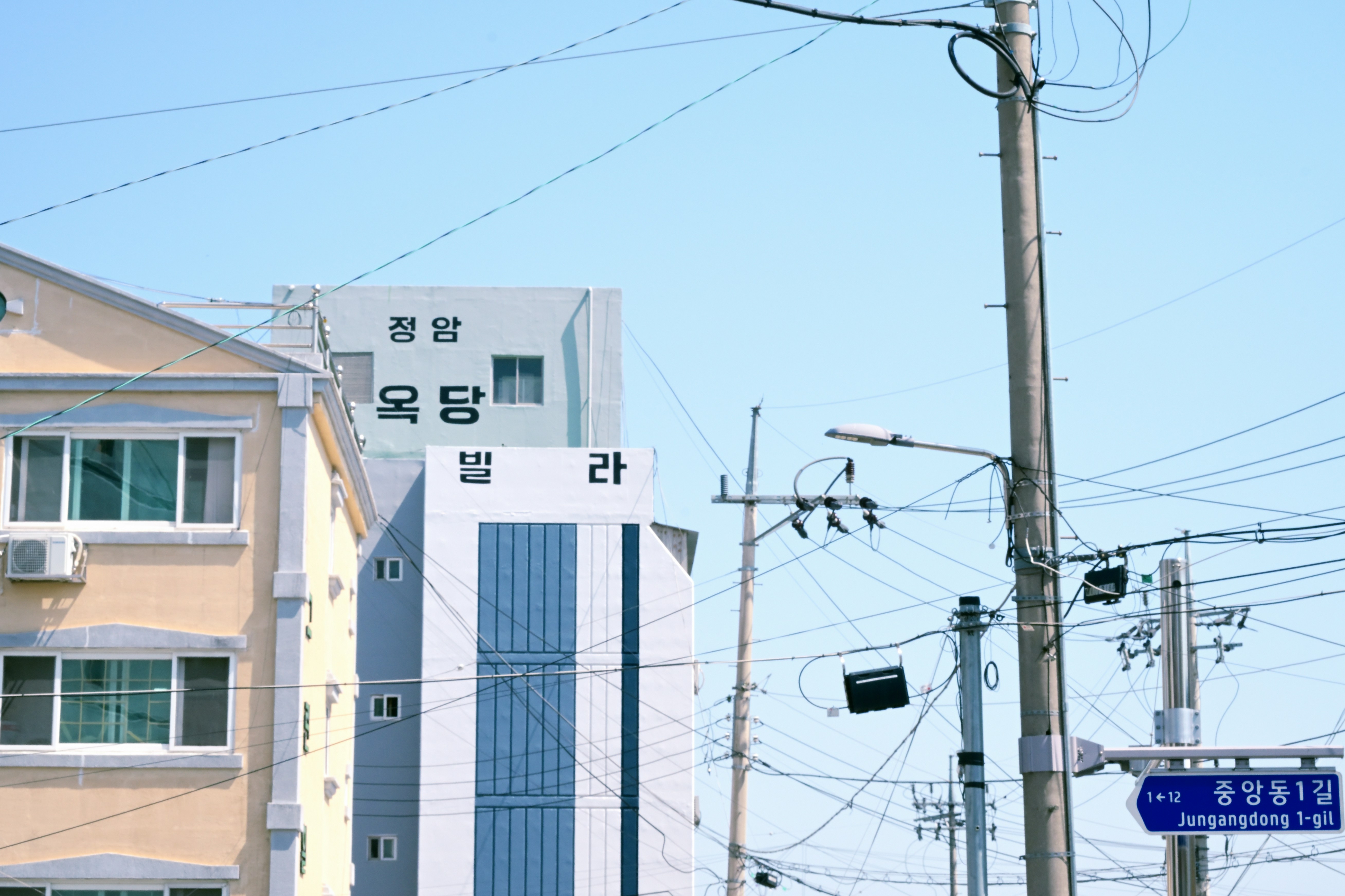 Neon-tinged City Facade Beneath a Web of Power Lines