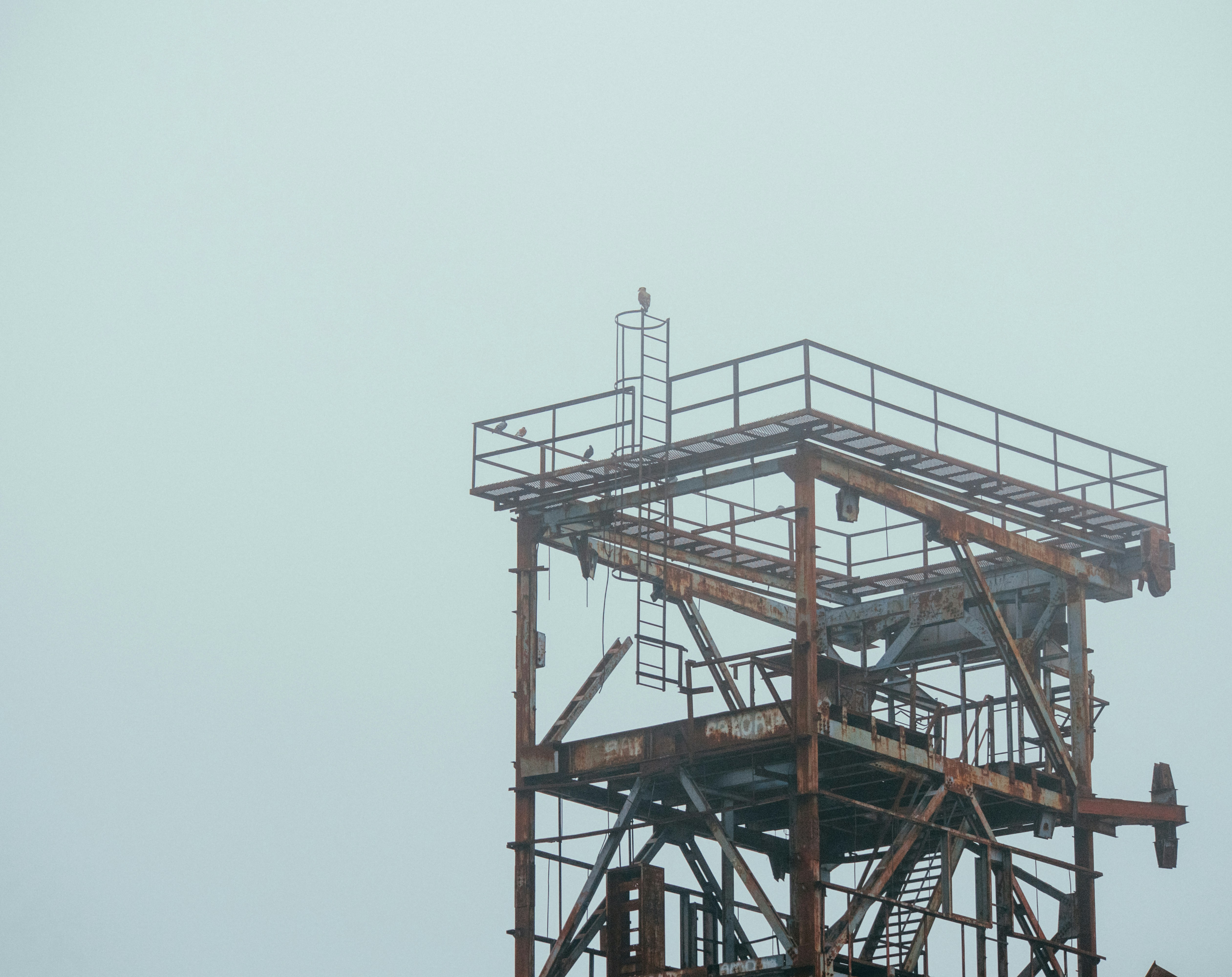 Rusty tower silhouette against pale sky