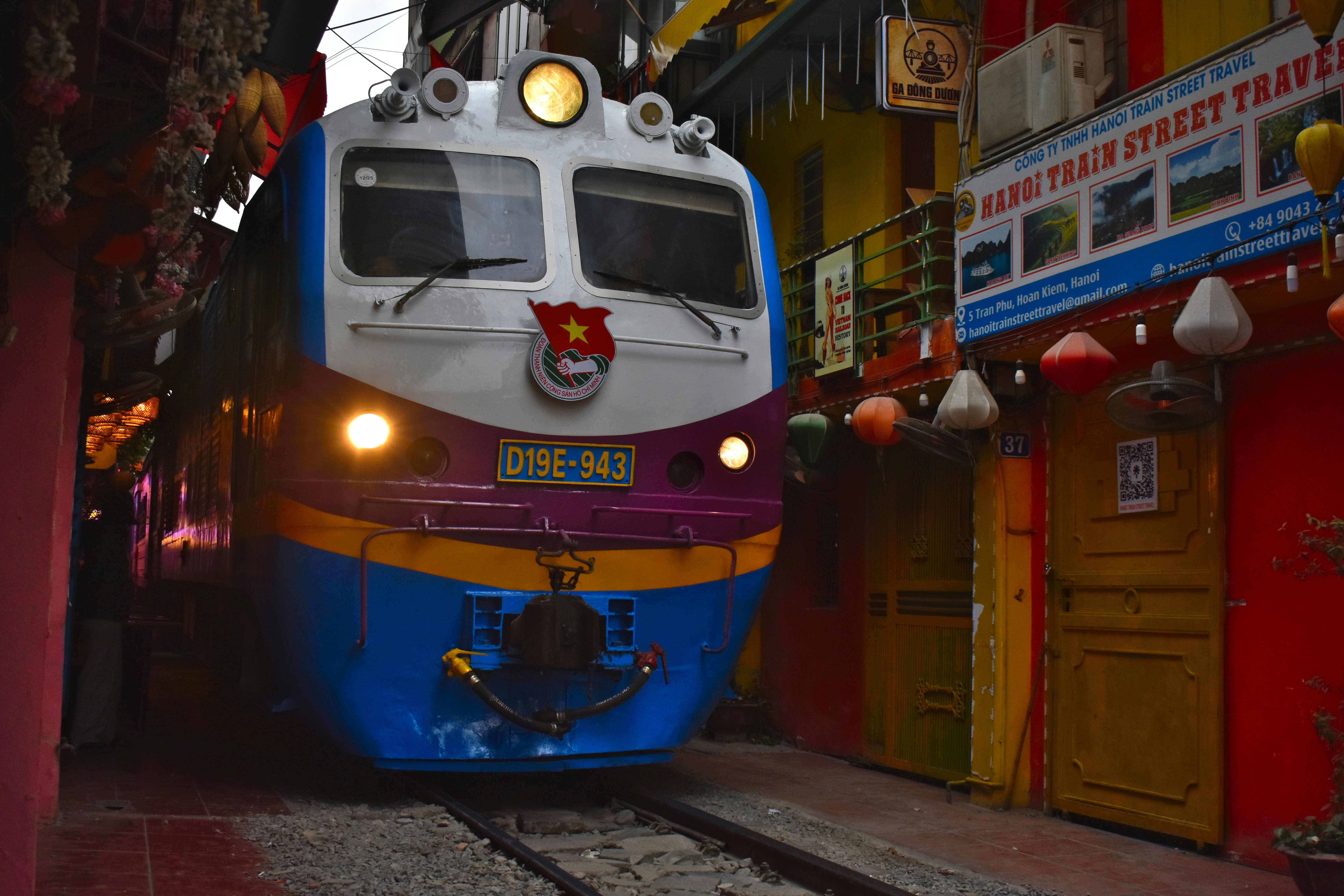 Diesel Enters the Alley: A Neon-Flected Locomotive in a Busy Market Corridor