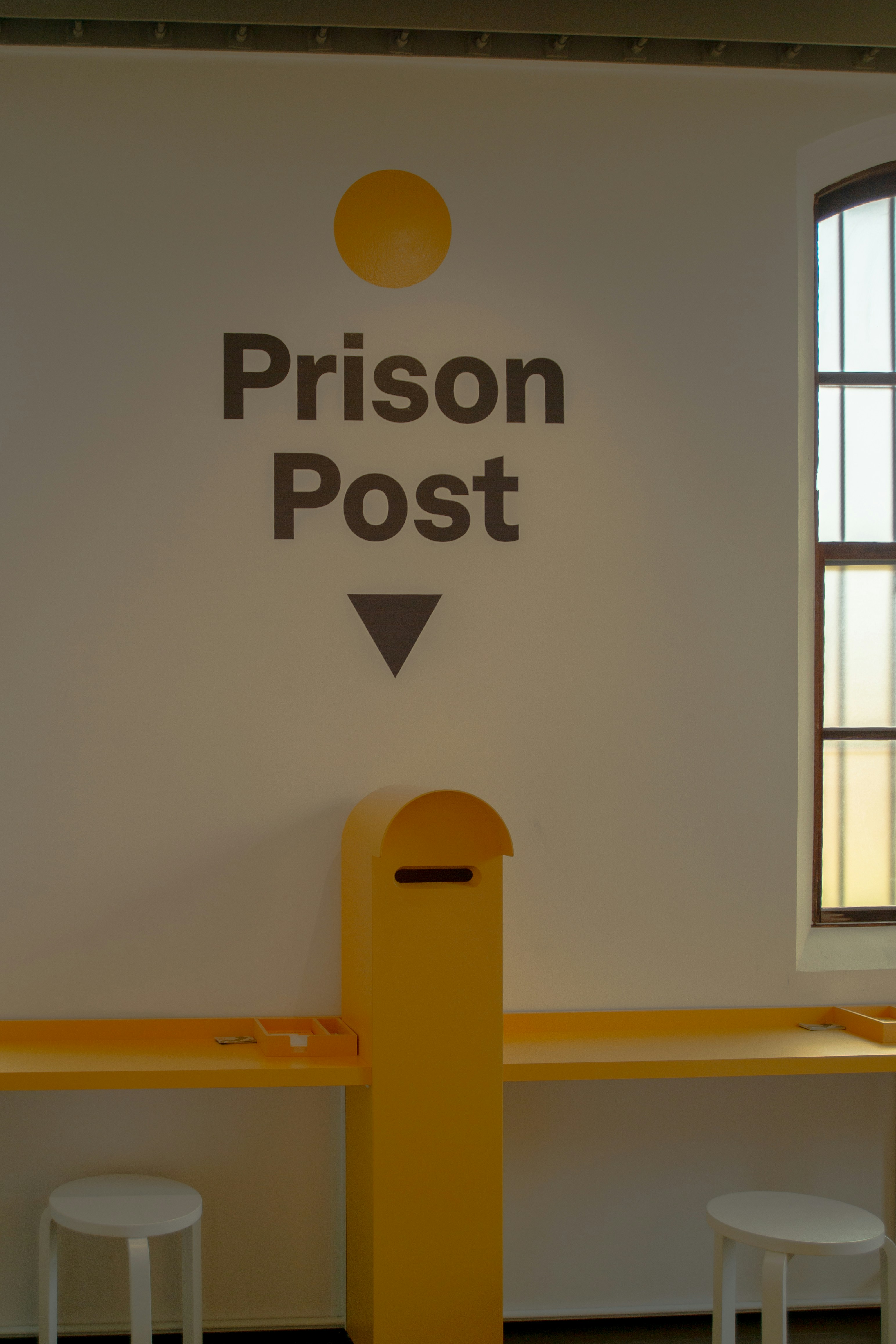 Yellow Postbox Station in Minimalist Prison Wall