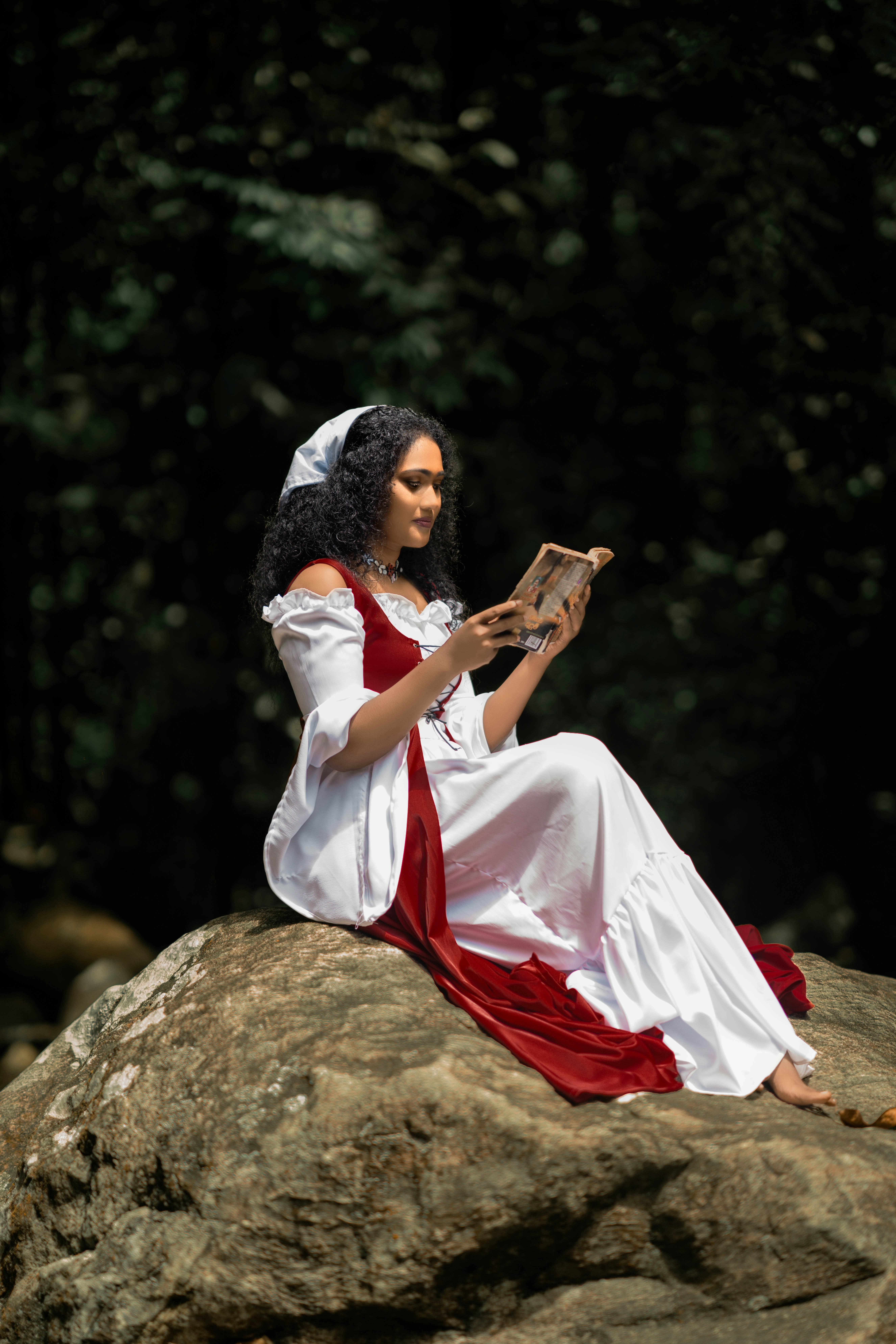 Castlewood Muse: A Woman in Period Attire Reading on a Sunlit Rock