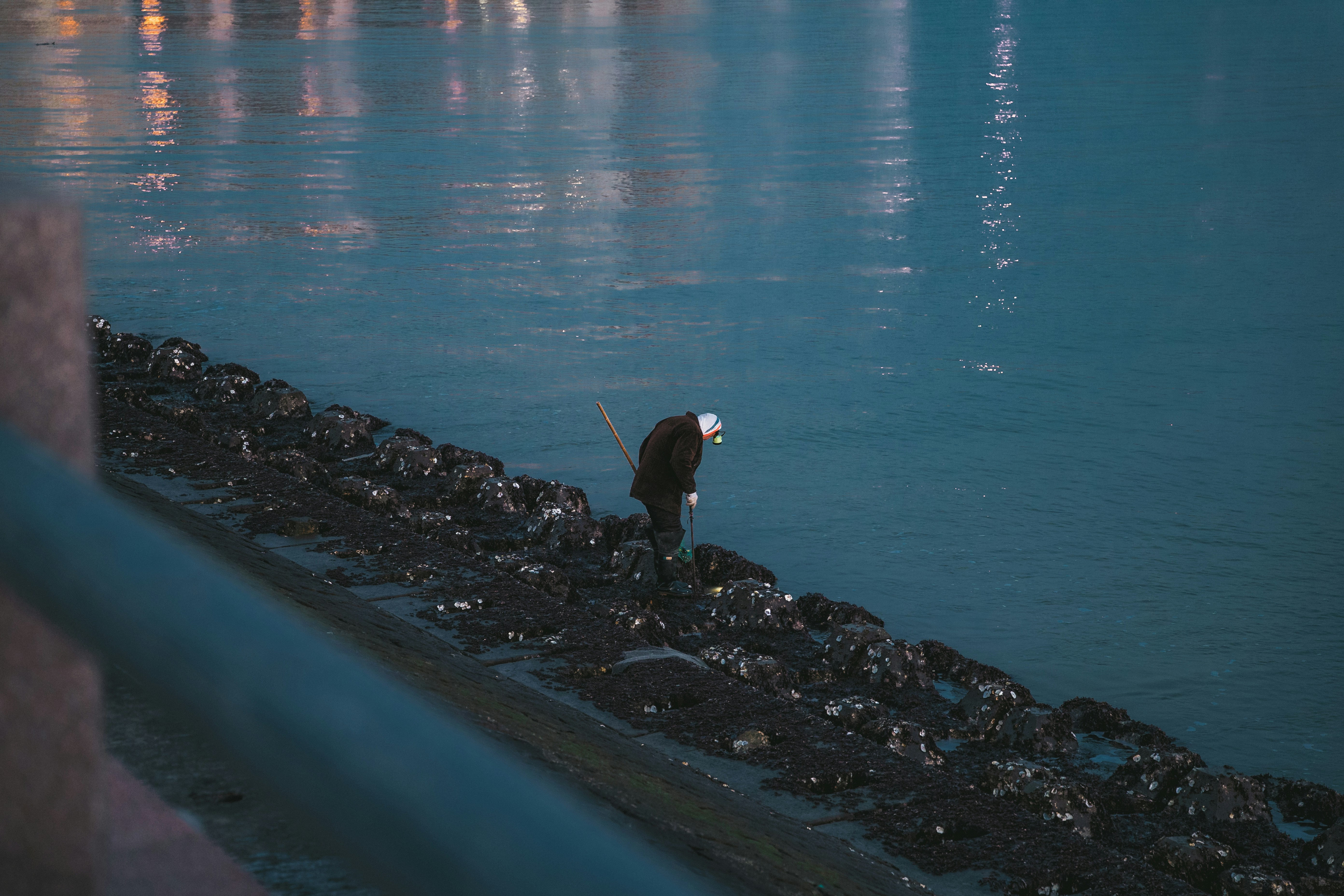 Lonely silhouette along the harbor stones under a calm blue glow
