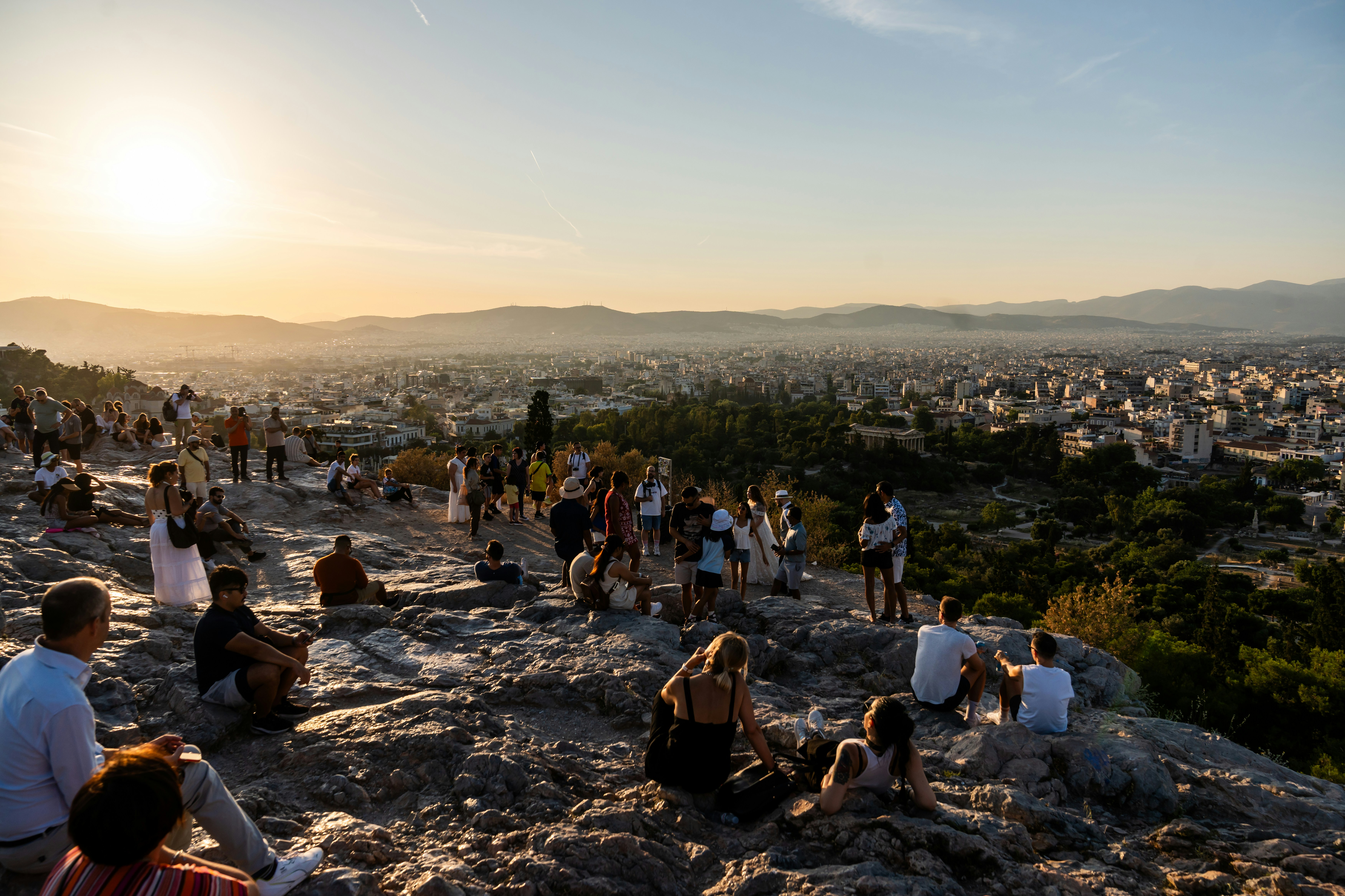 Sunset Gathering on the Cliff: City Silhouette and Distant Mountains